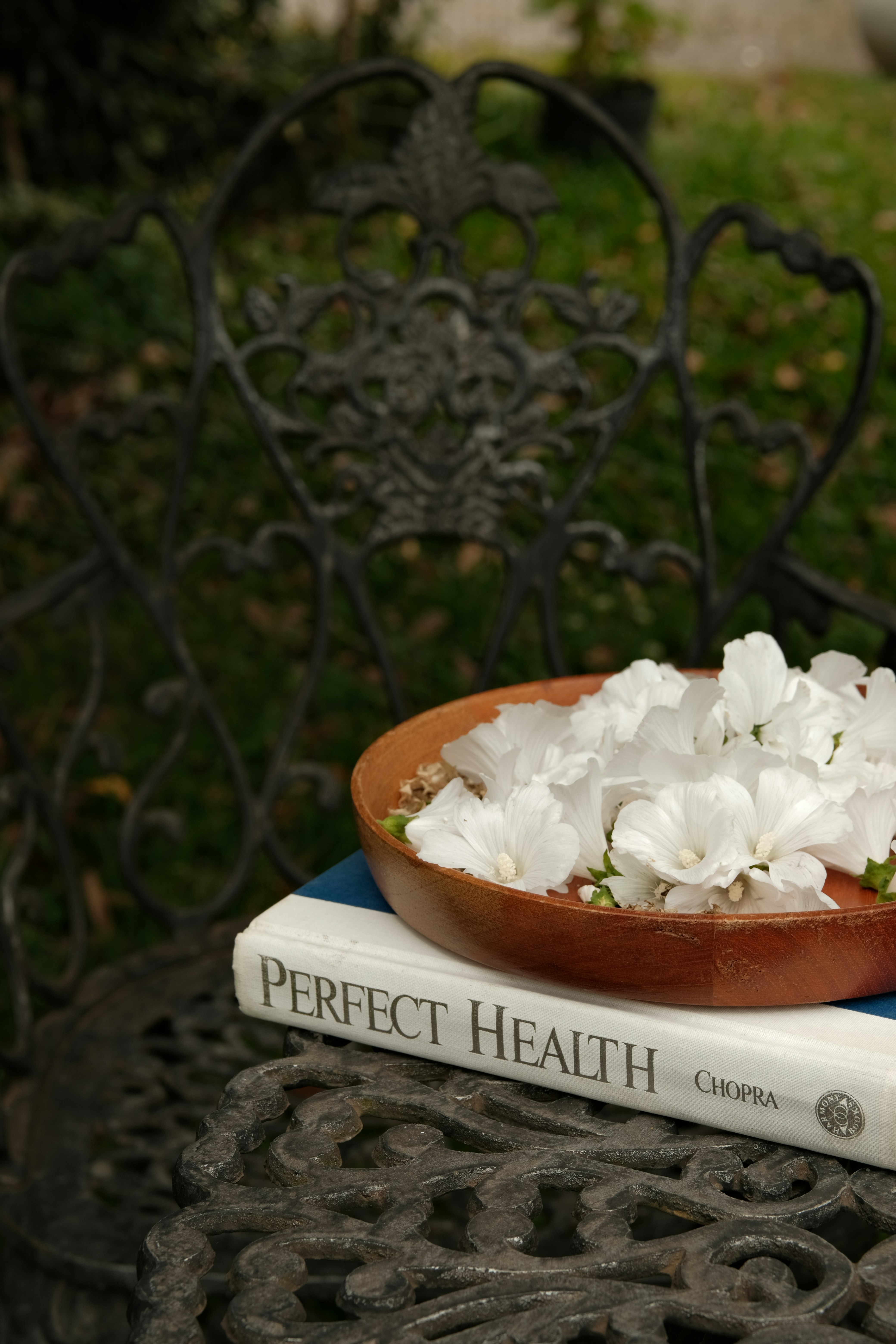 White Flowers in a Wooden Bowl resting on a Well-Worn Book