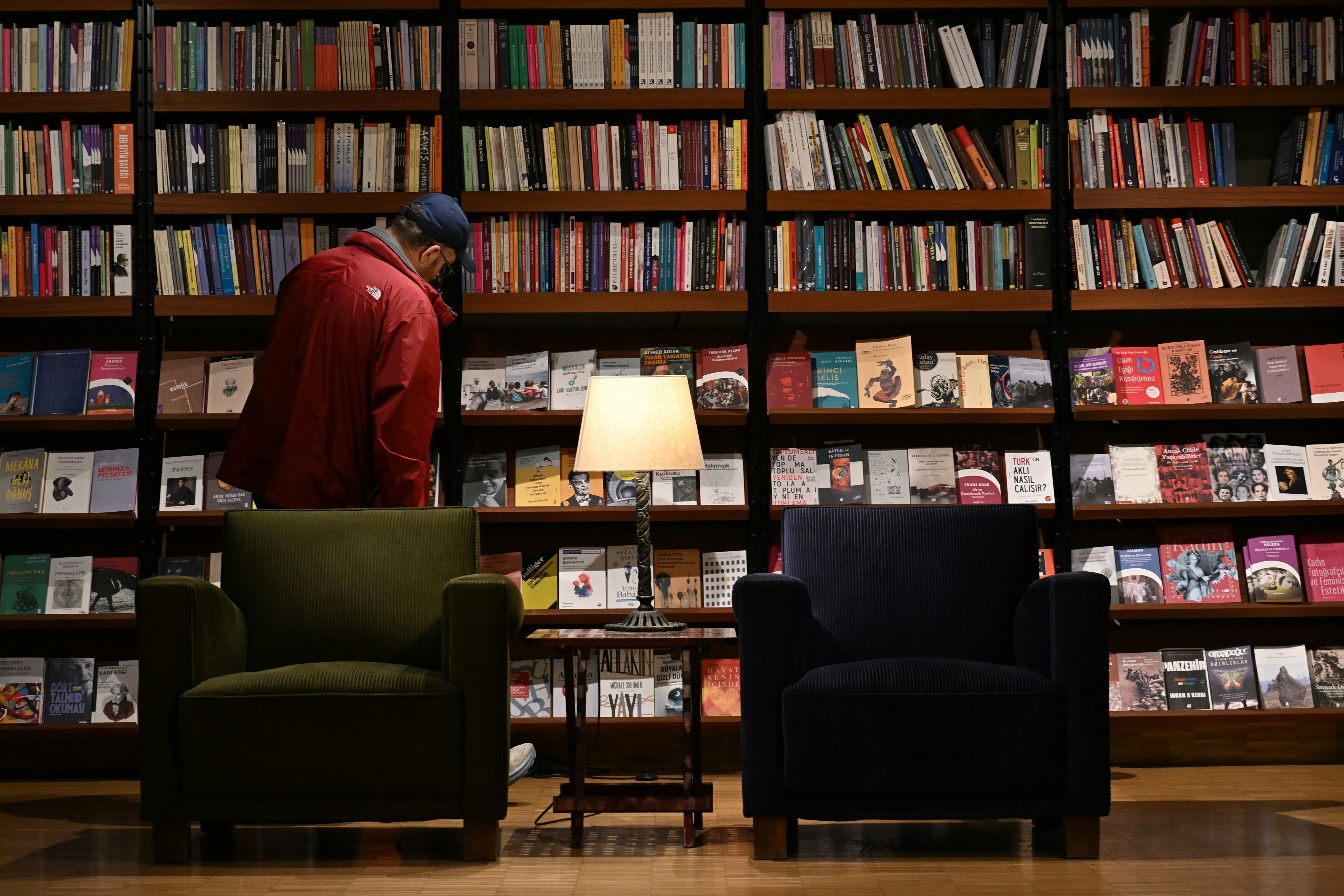 Man browsing books in a library with chairs and chairs.