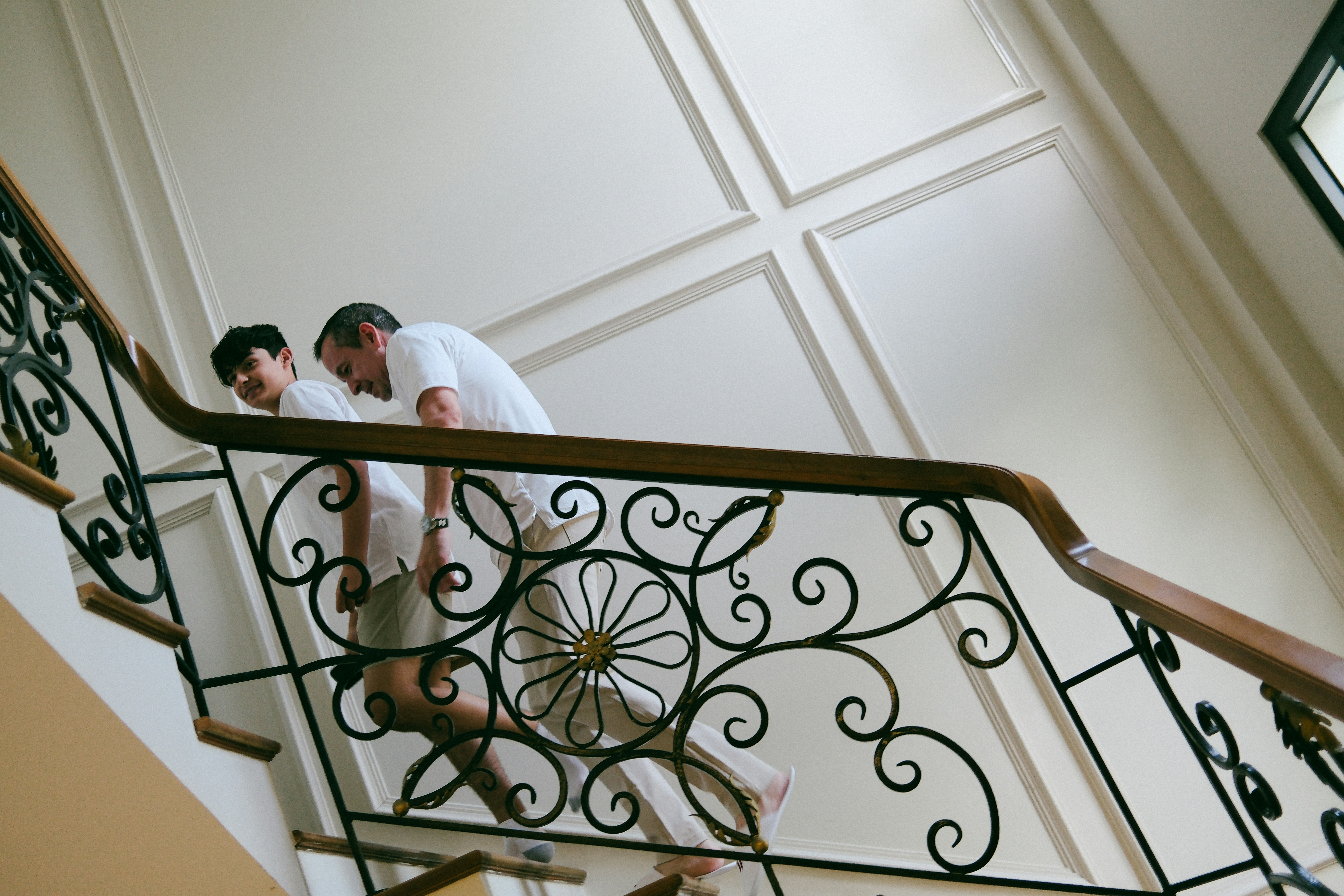 Ascending along the wrought-iron spiral: three figures on a sunlit stair