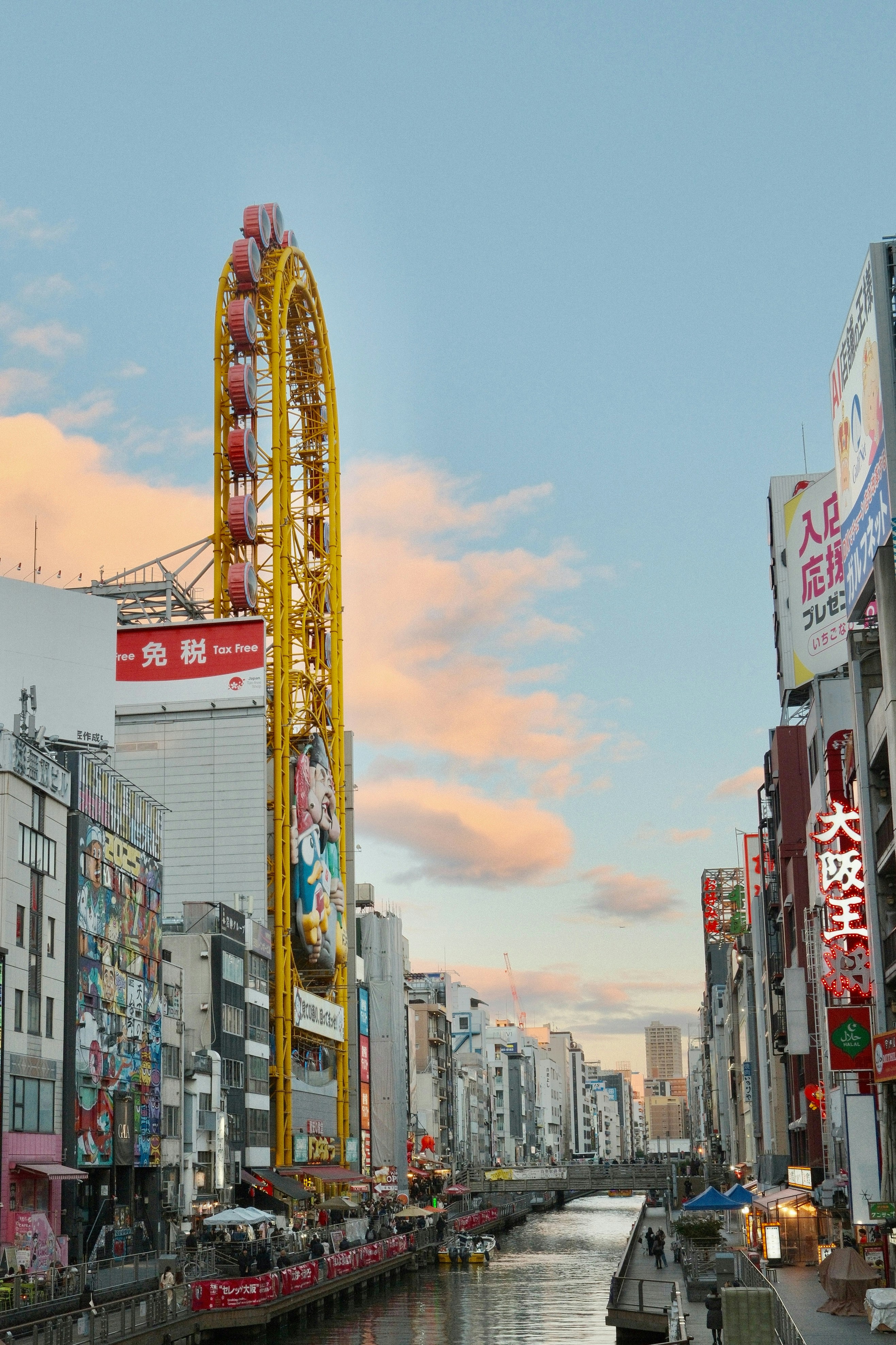 Sunlit Ferris Wheel Over a Bustling City Canal