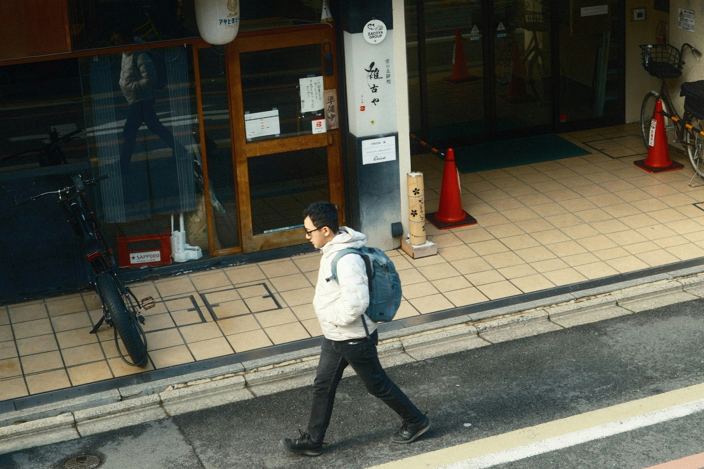 Quiet stride: commuter with backpack in a city storefront corridor