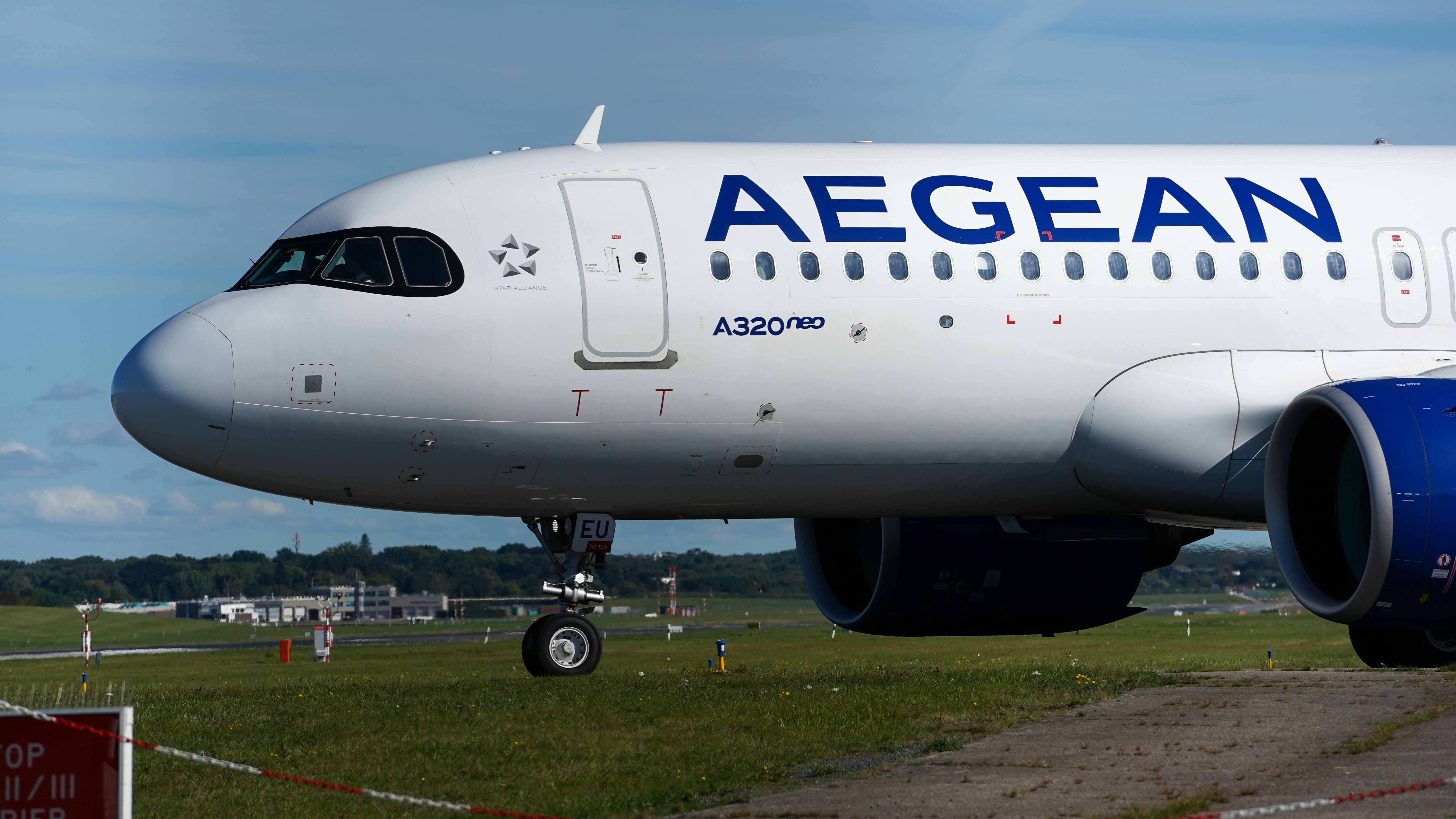 Aegean Flight at Ground Level: Front View of A320neo on a Sunlit Taxiway