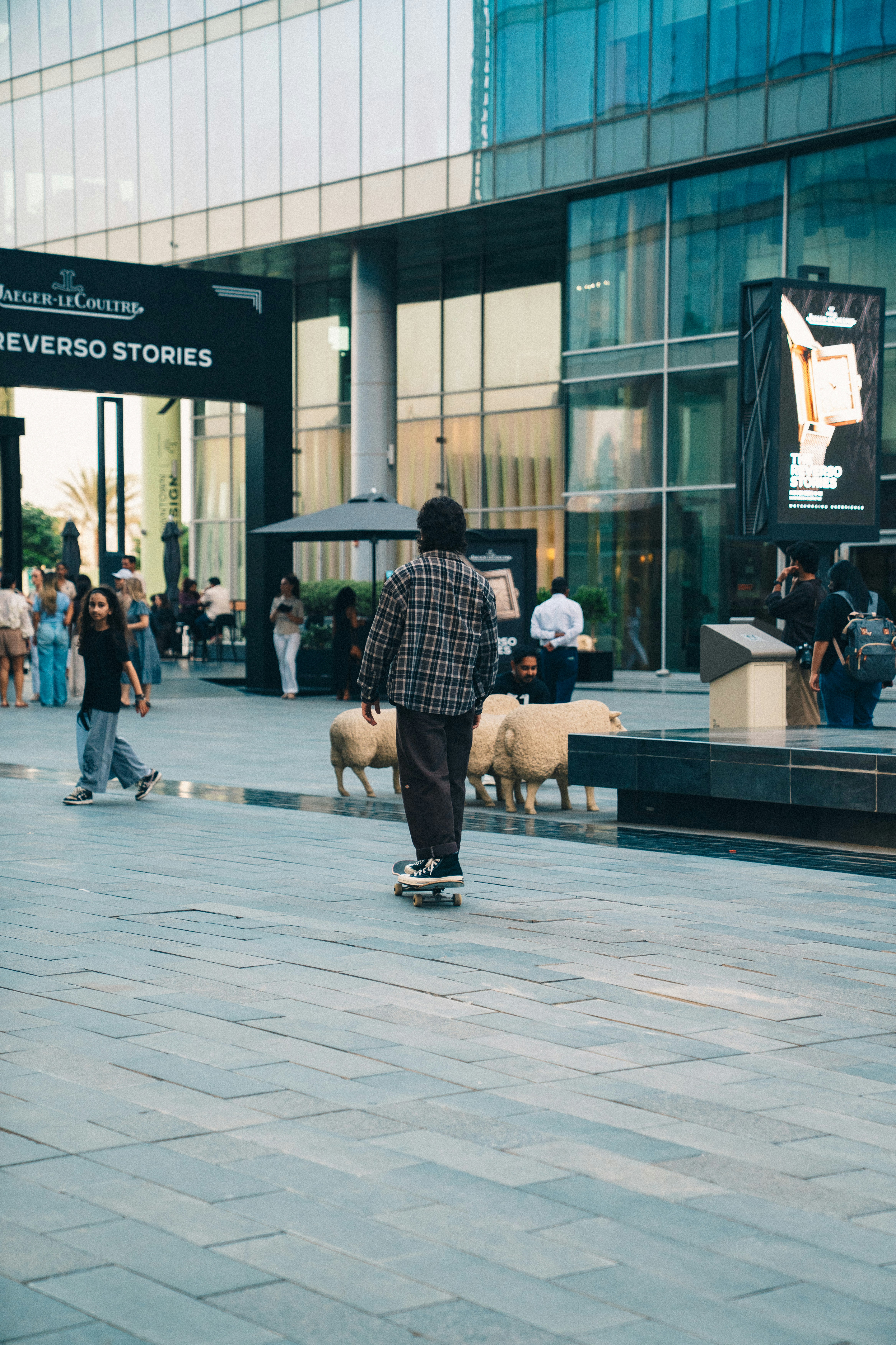 Skateboarder in a Modern Courtyard Surrounded by Glass and Sheep (Urban Scene)