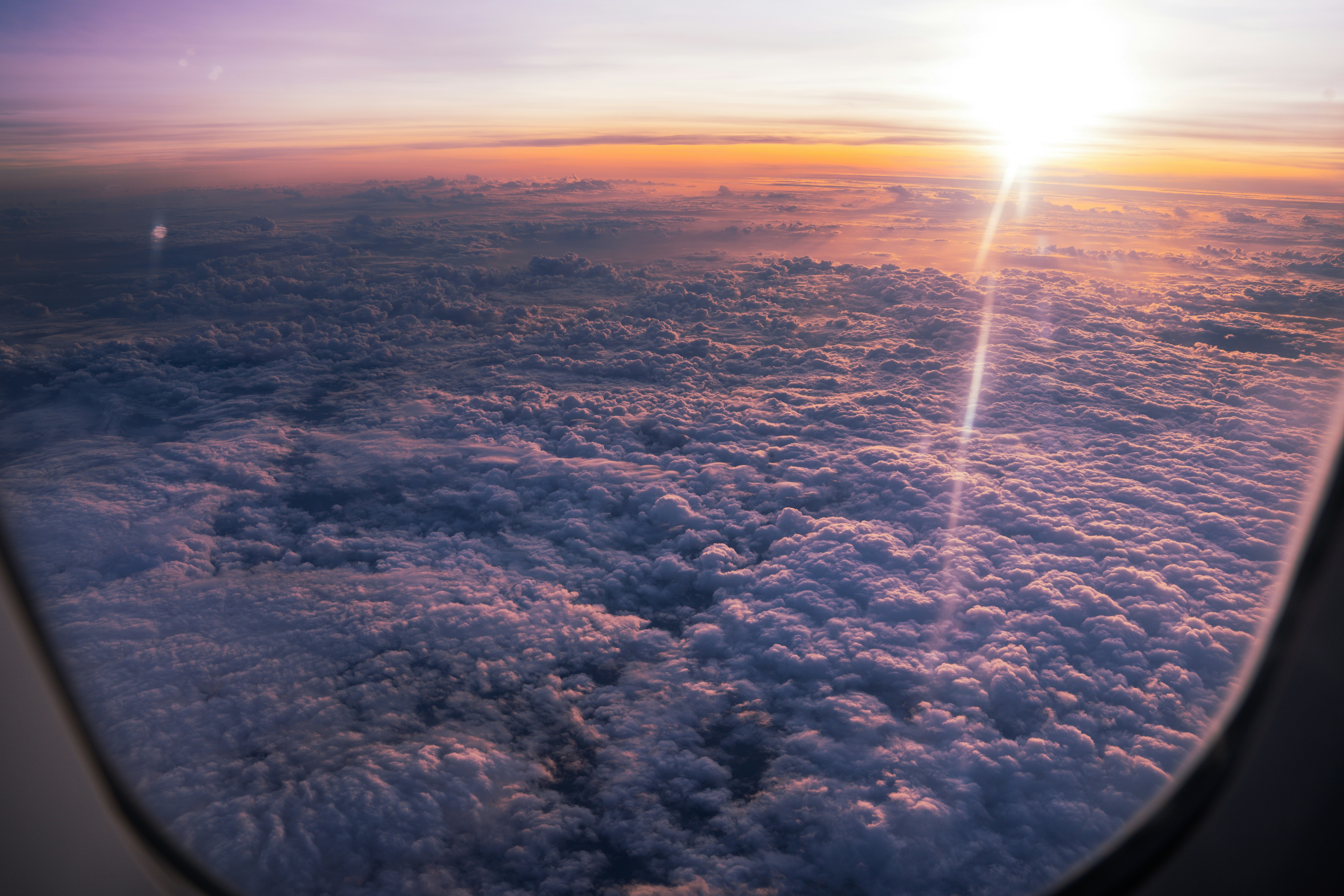 Golden sunlight hitting the horizon line above a thick layer of clouds. A dramatic nature shot showing the vast atmosphere during golden hour