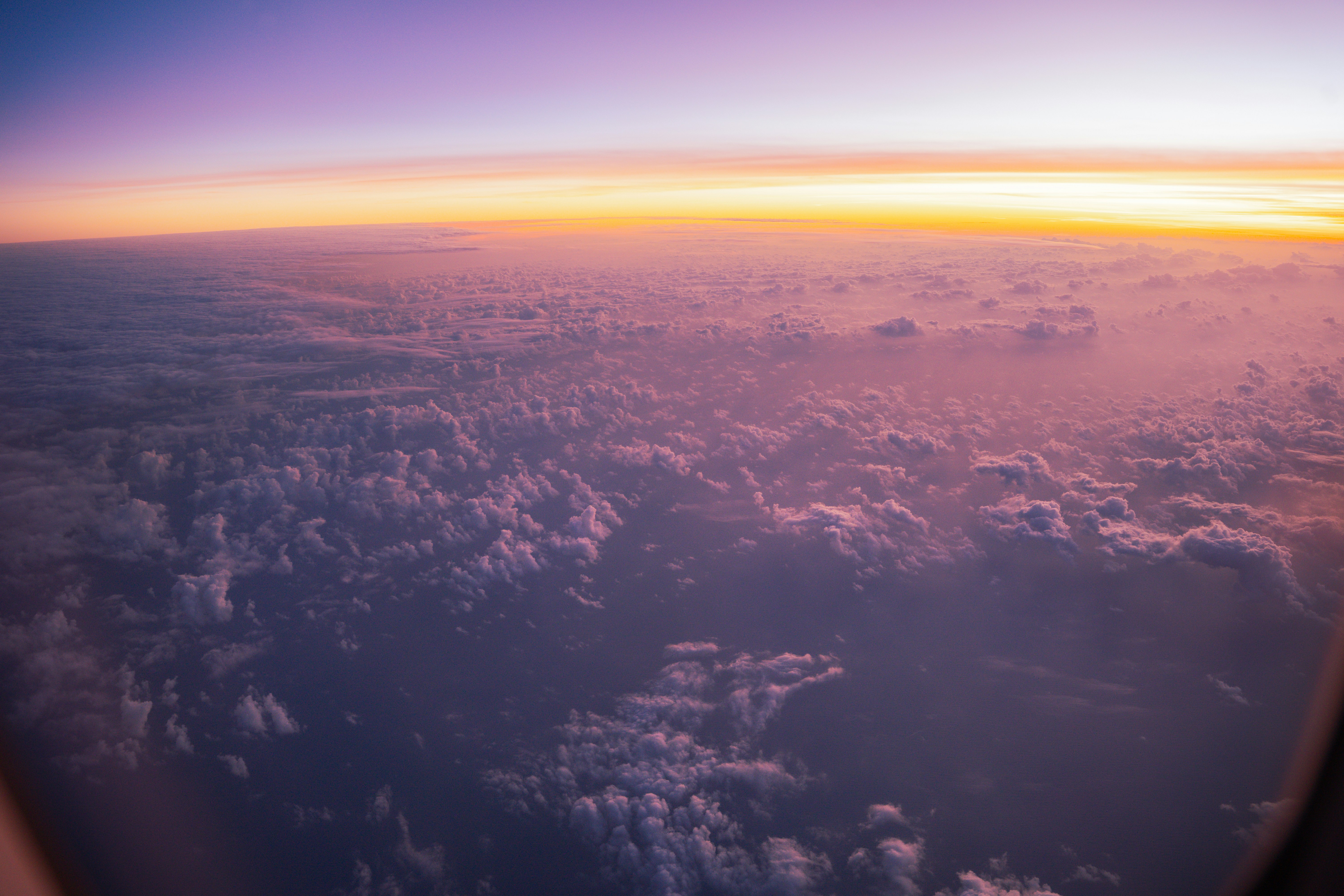 Golden sunlight hitting the horizon line above a thick layer of clouds. A dramatic nature shot showing the vast atmosphere during golden hour