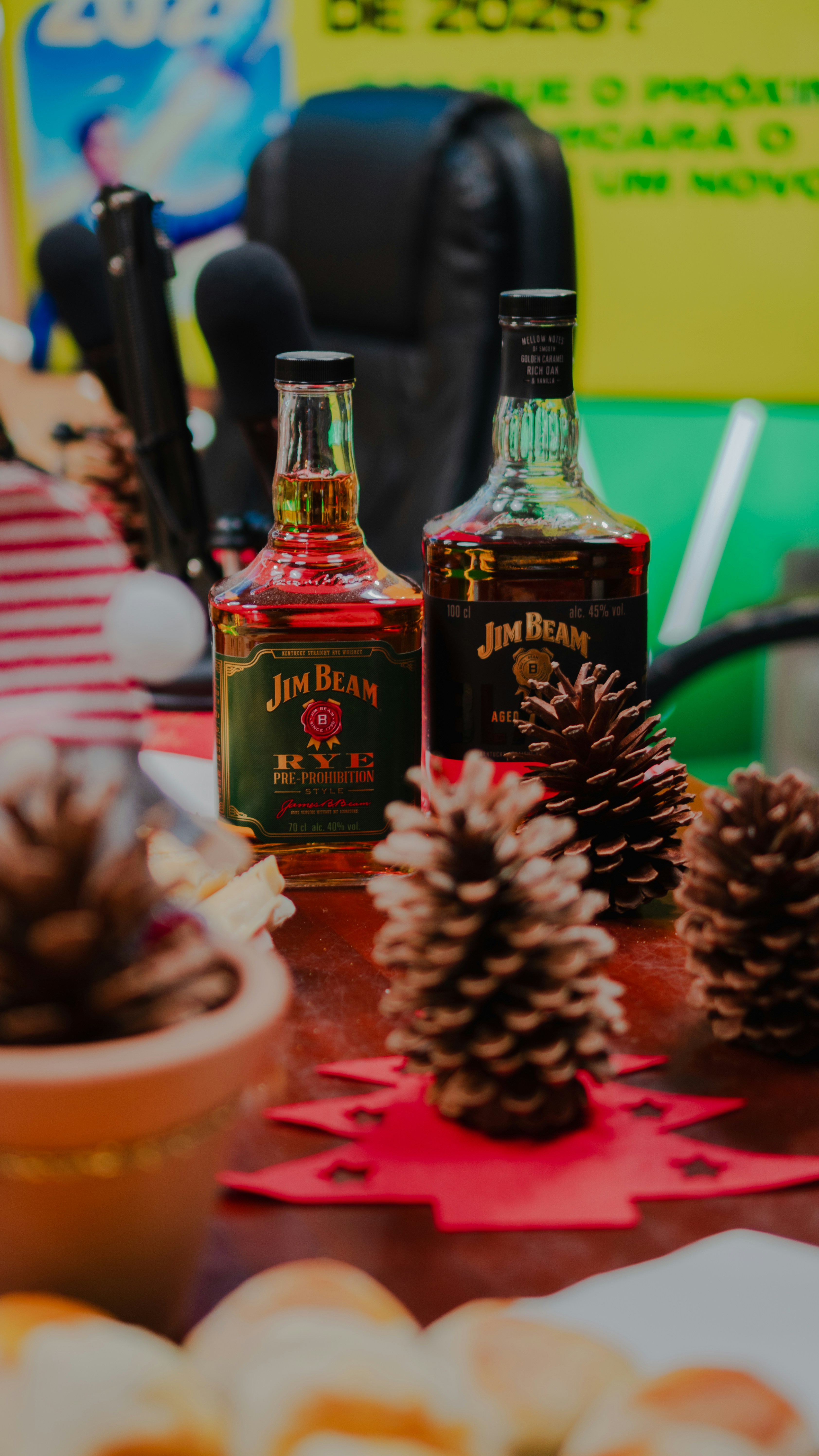 Two whiskey bottles on a festive table with pinecones foreground