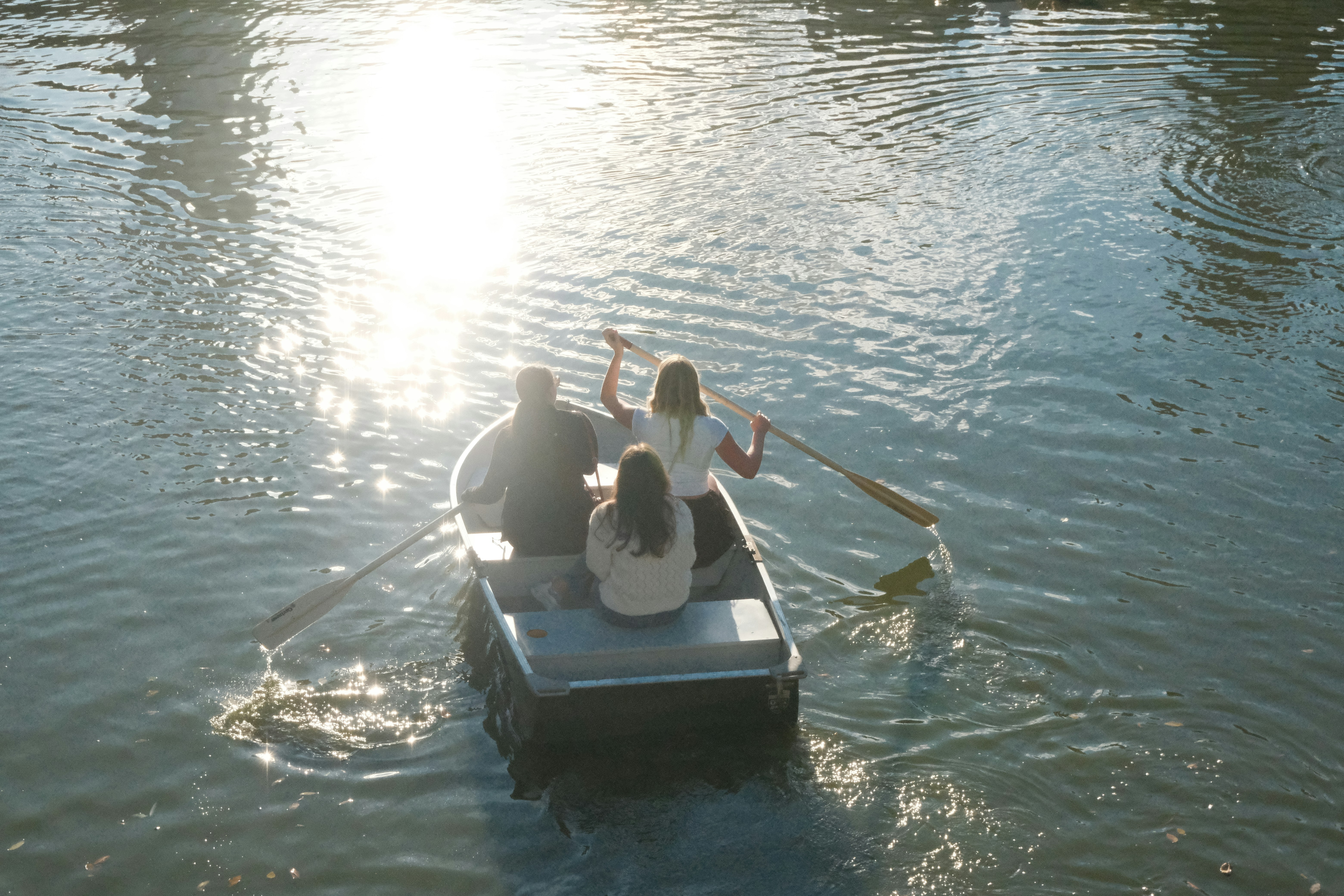 Sunlit Rowboat: Three Friends Cherish a Quiet Moment on the River