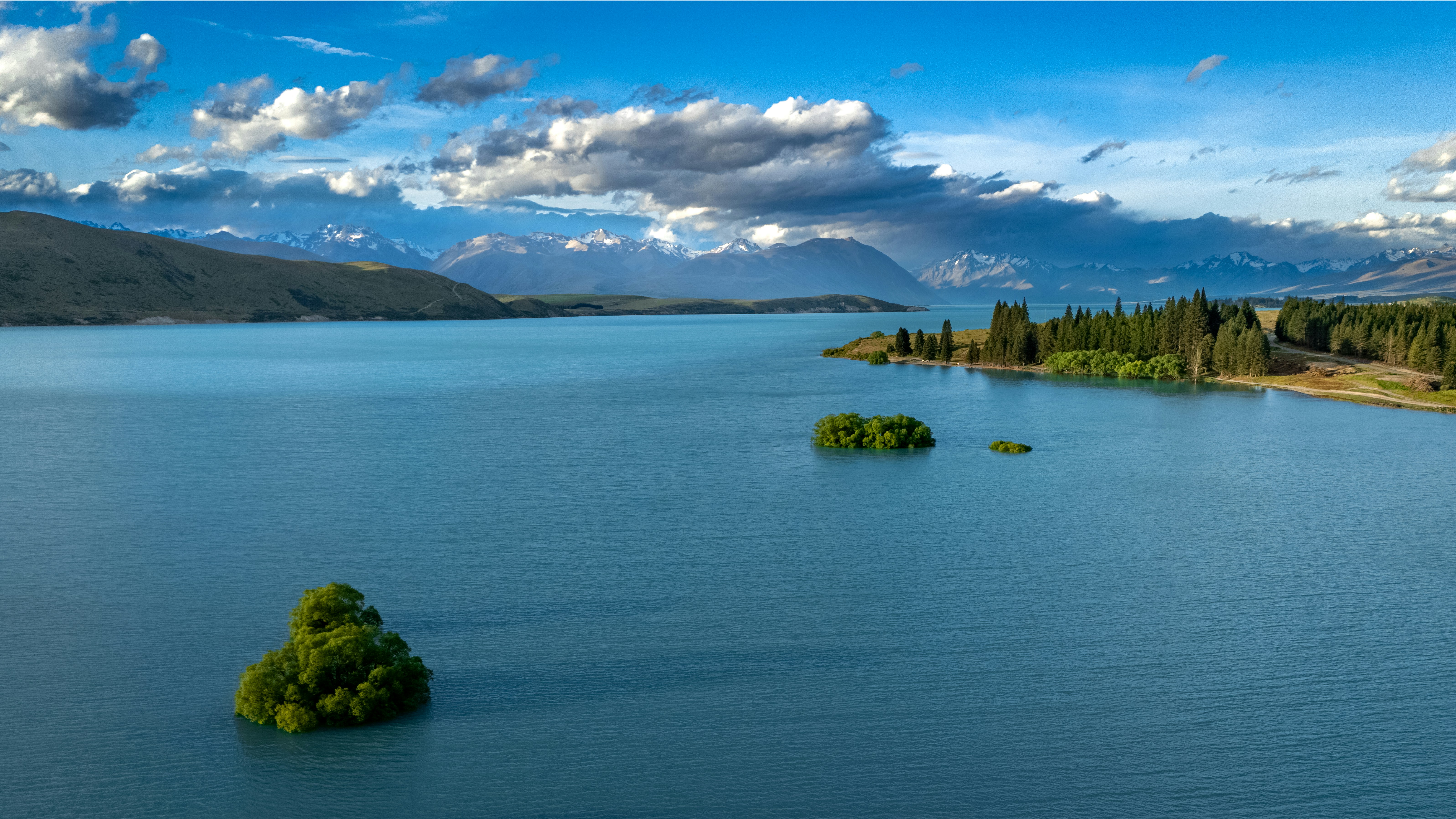 Vast blue lake with islands and distant mountains.
