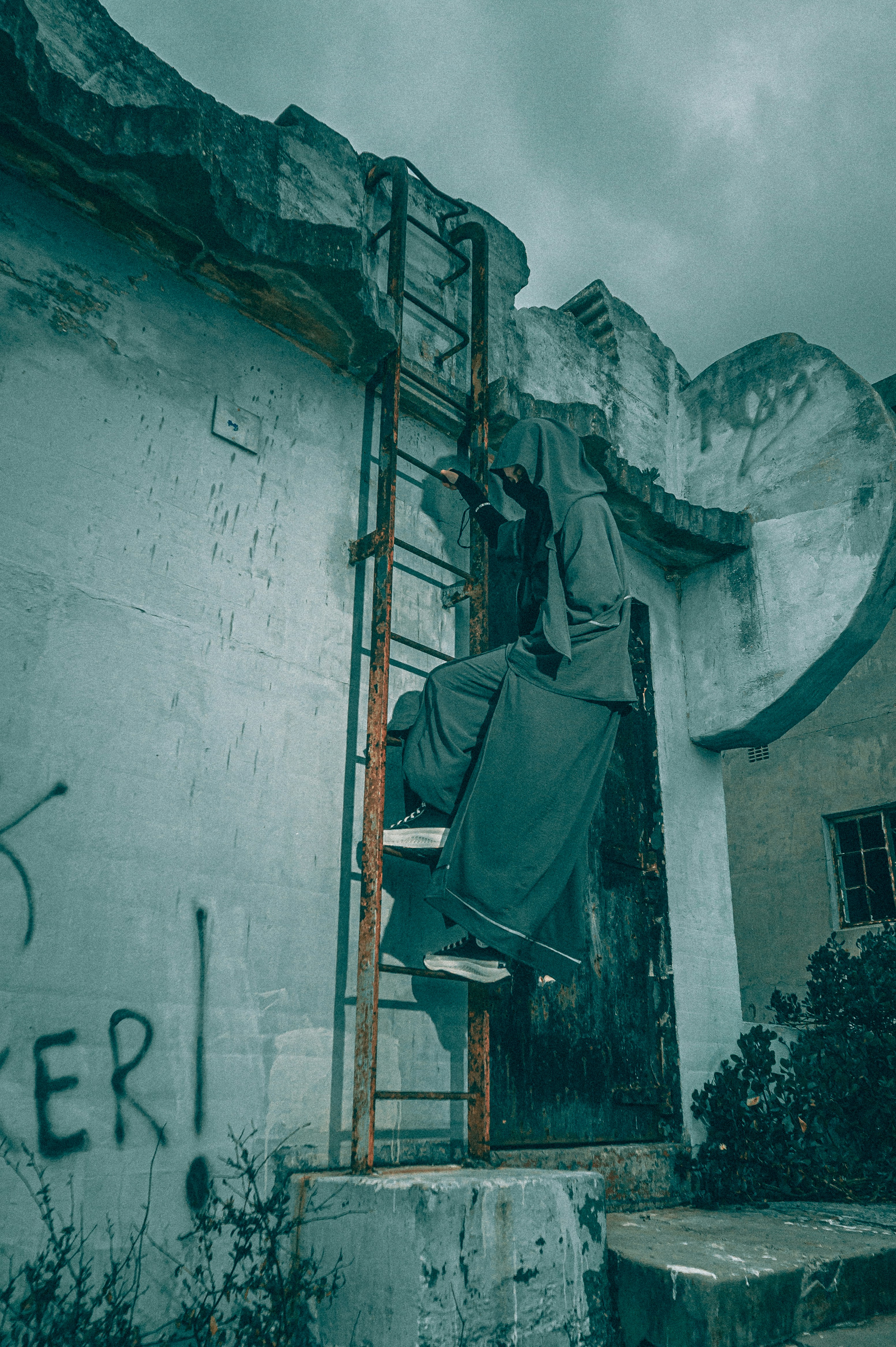 Climbing Through Decay: A Hooded Figure Ascends a Rusted Ladder