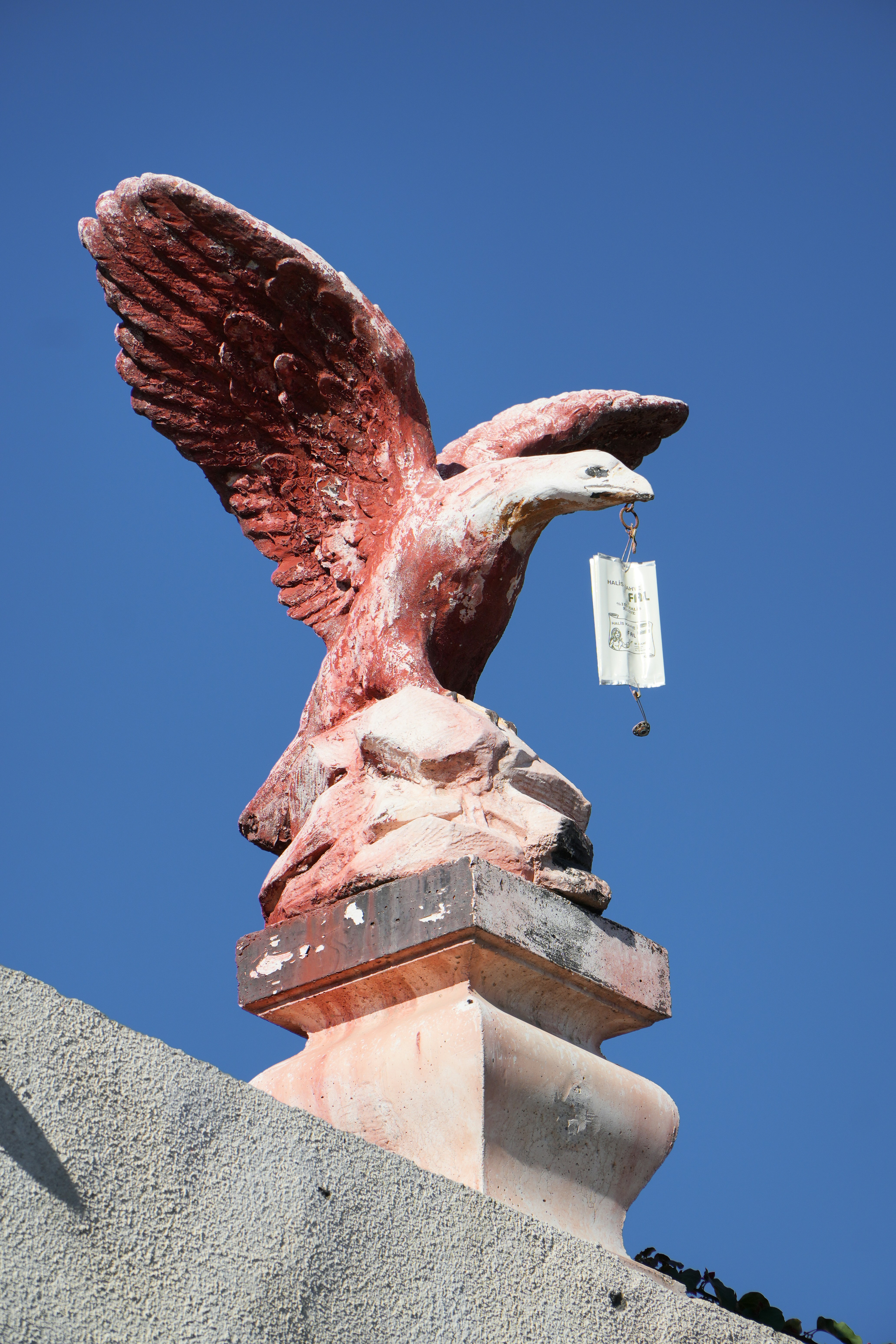 Red-winged guardian: weathered eagle statue under a clear blue sky