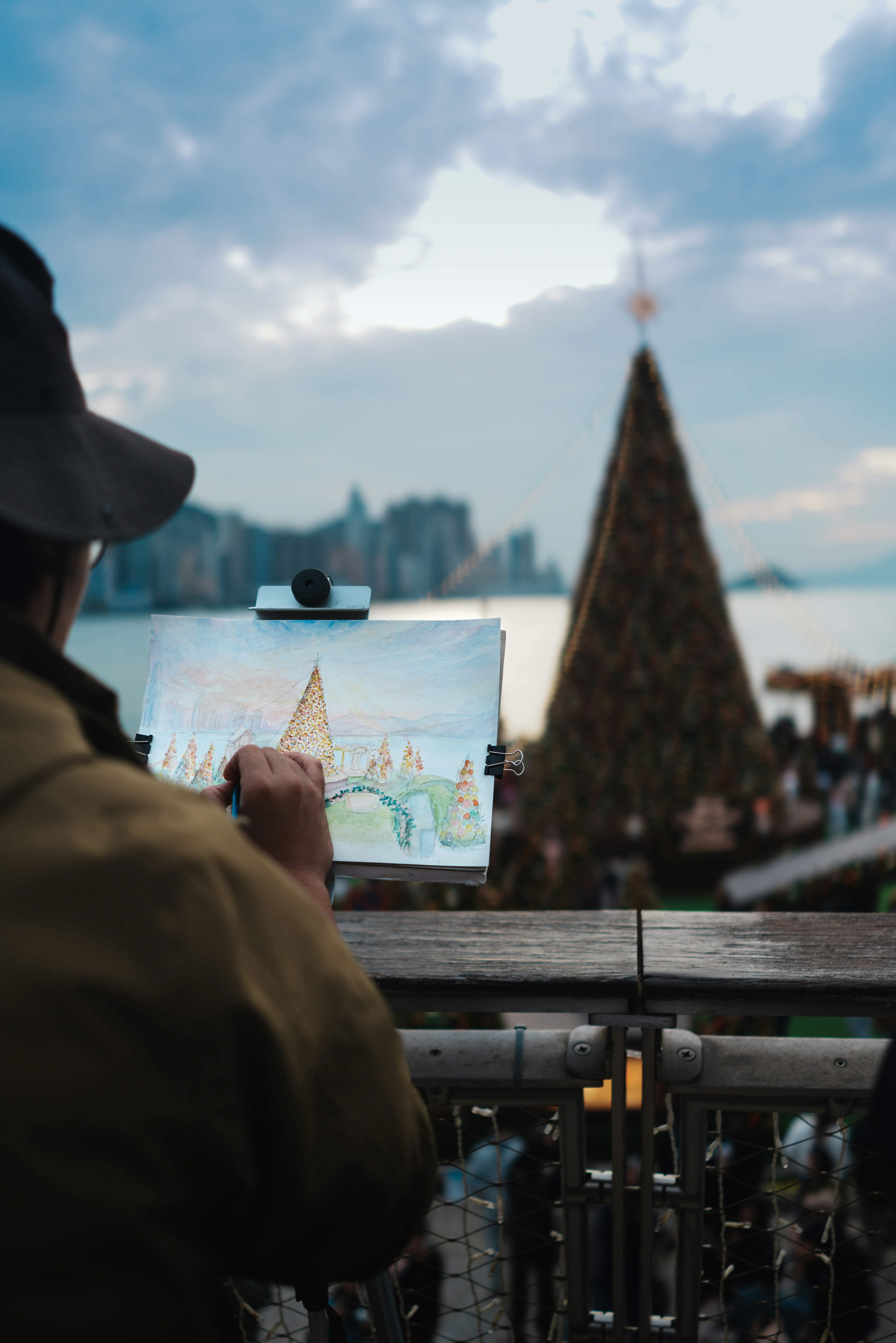Artist paints a cityscape with a christmas tree.