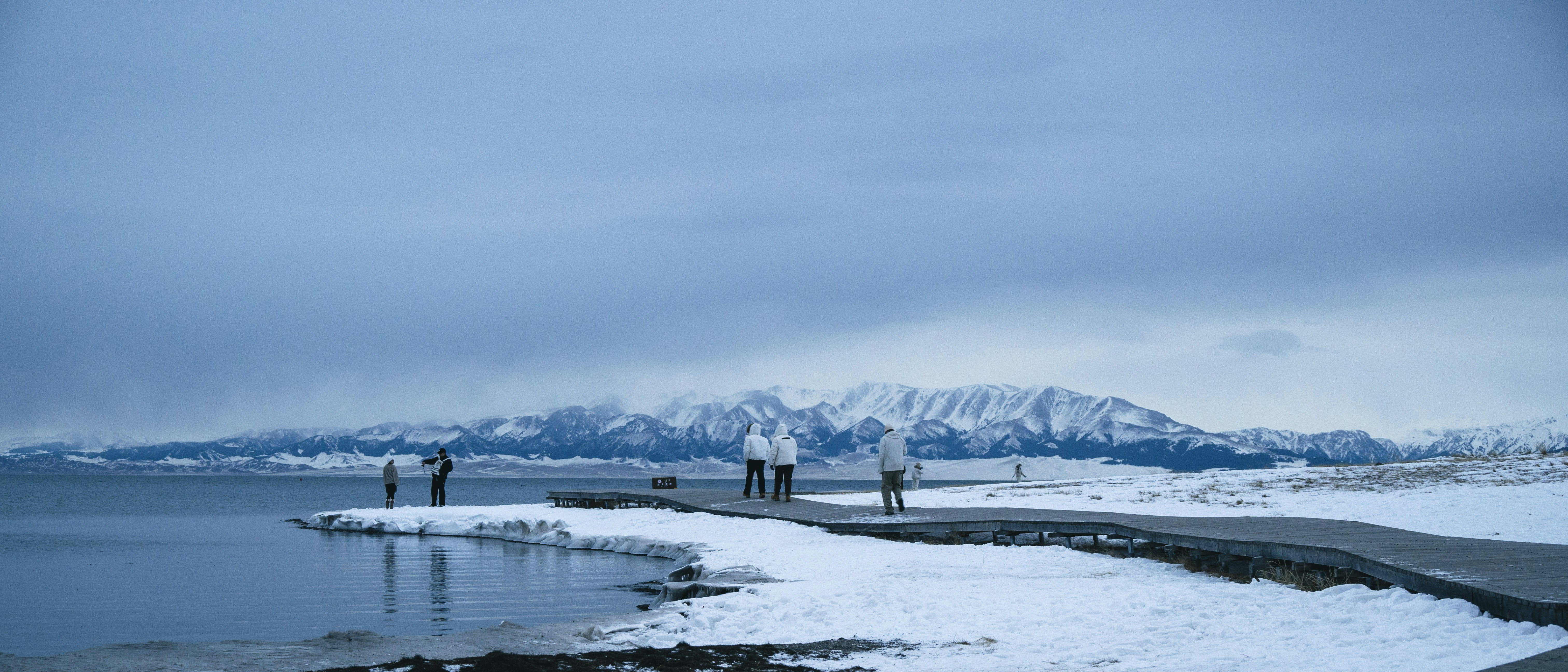 Snowbound Promenade: Figures on a Quiet Barrow of Ice and Mountains