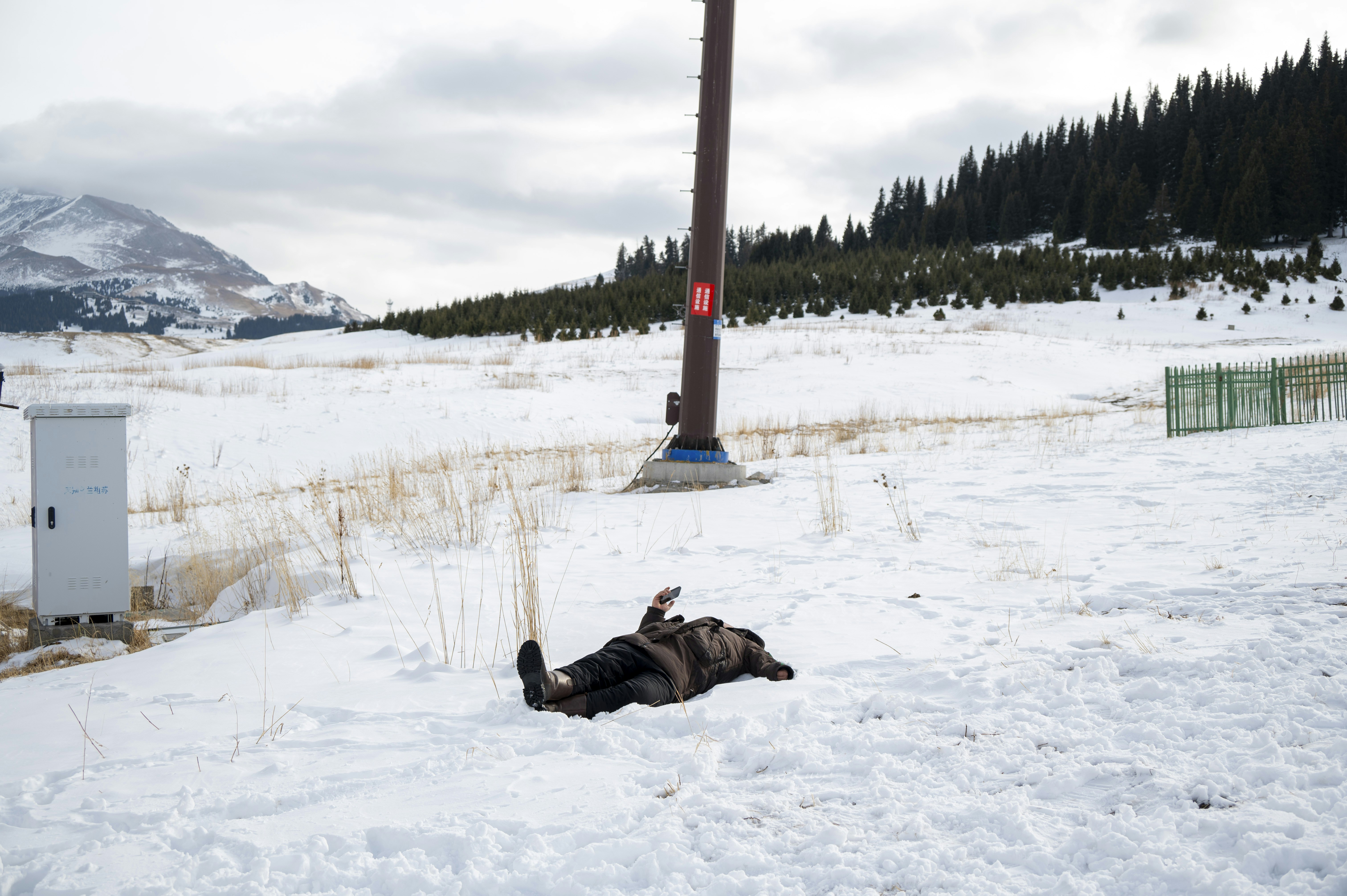 Snowfield Rest: A Lone Figure Reposes Under a Distant Mountain