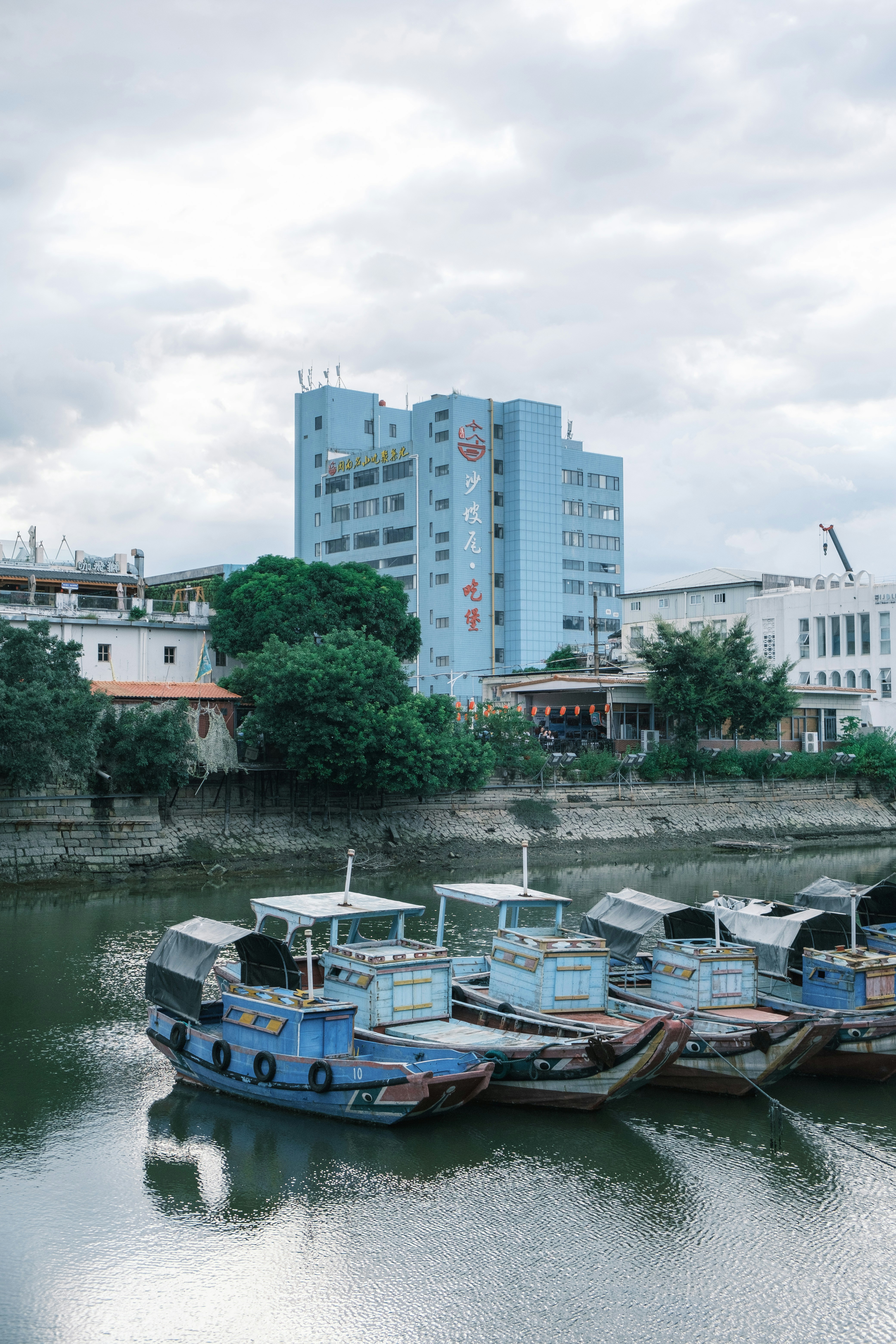 Blue Riverside Towers Over Quiet Docked Boats