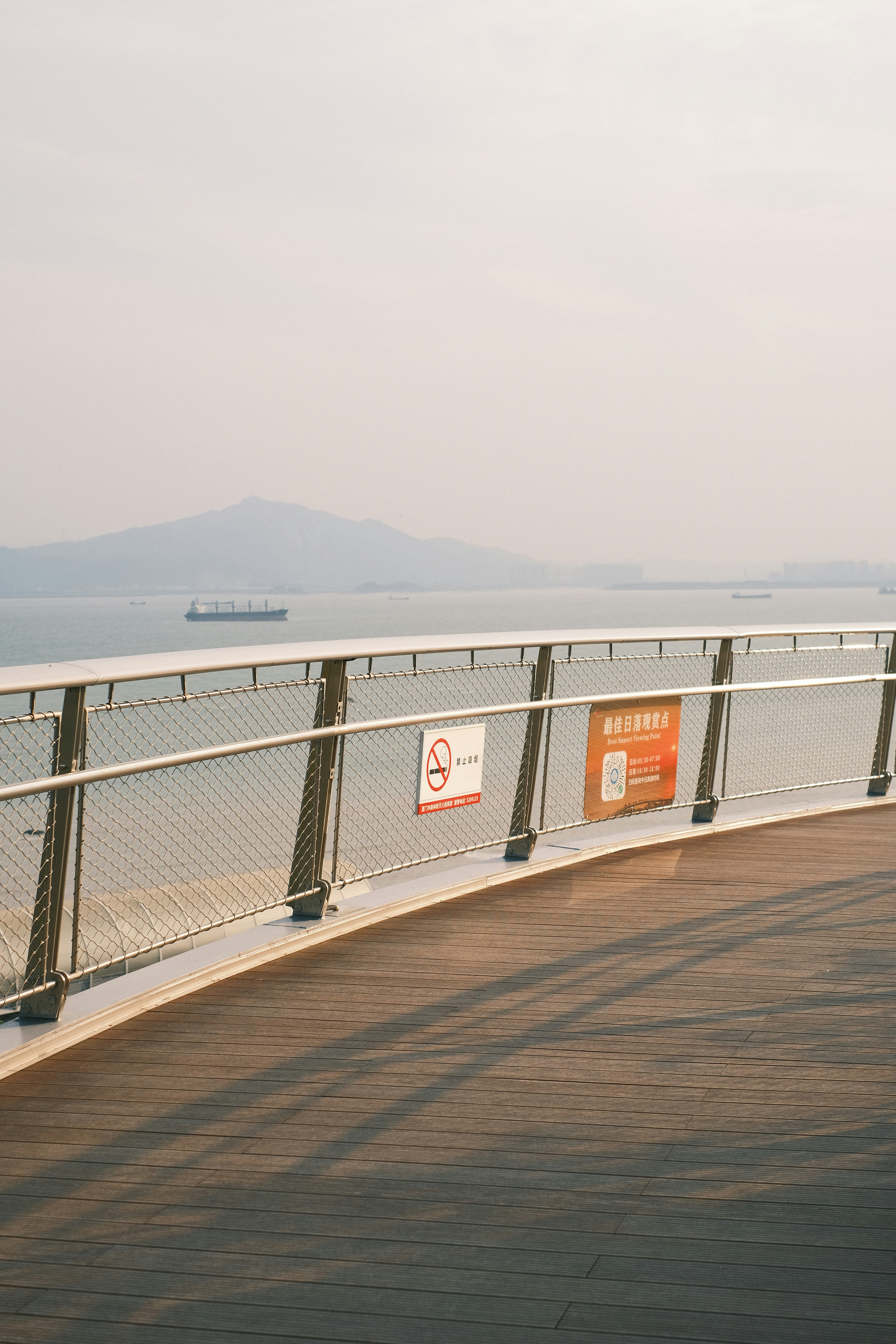 Curved Boardwalk Overlooking a Hazy Harbor