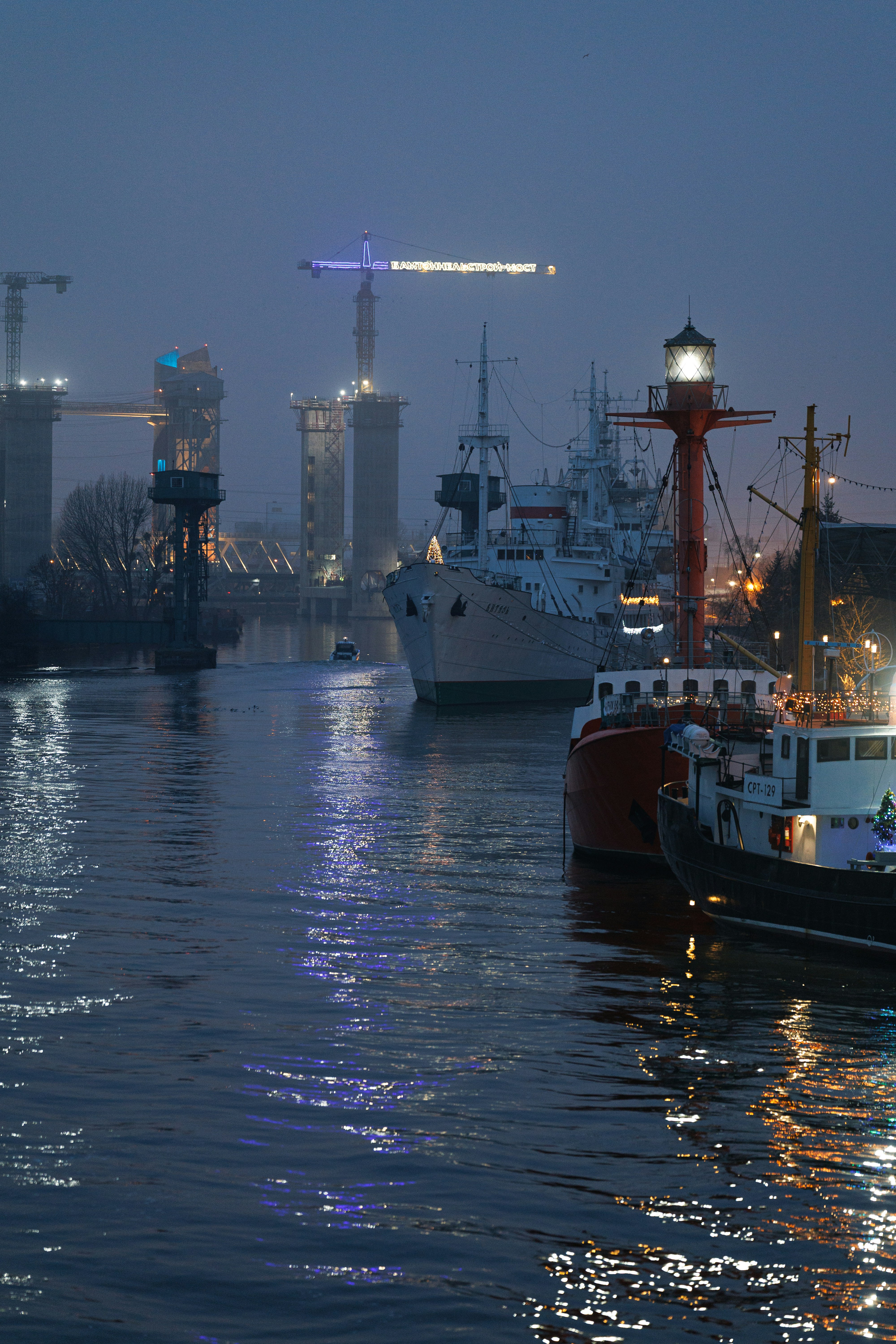 Harbor at Dusk: Ships and Crane Lights Echo on Calm Water