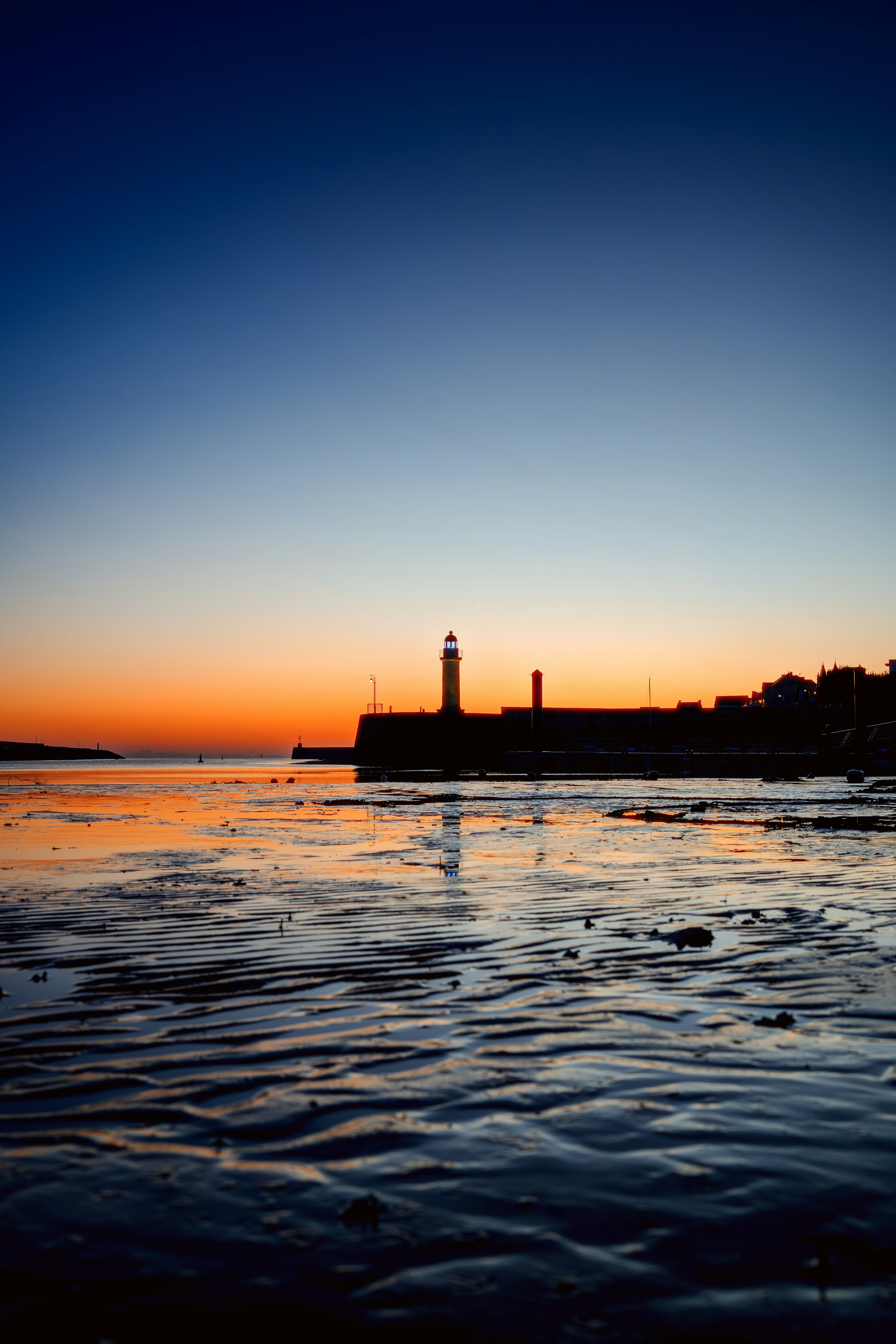 Glass-Gold Horizon: A Lighthouse Stands Against the Quiet Tide