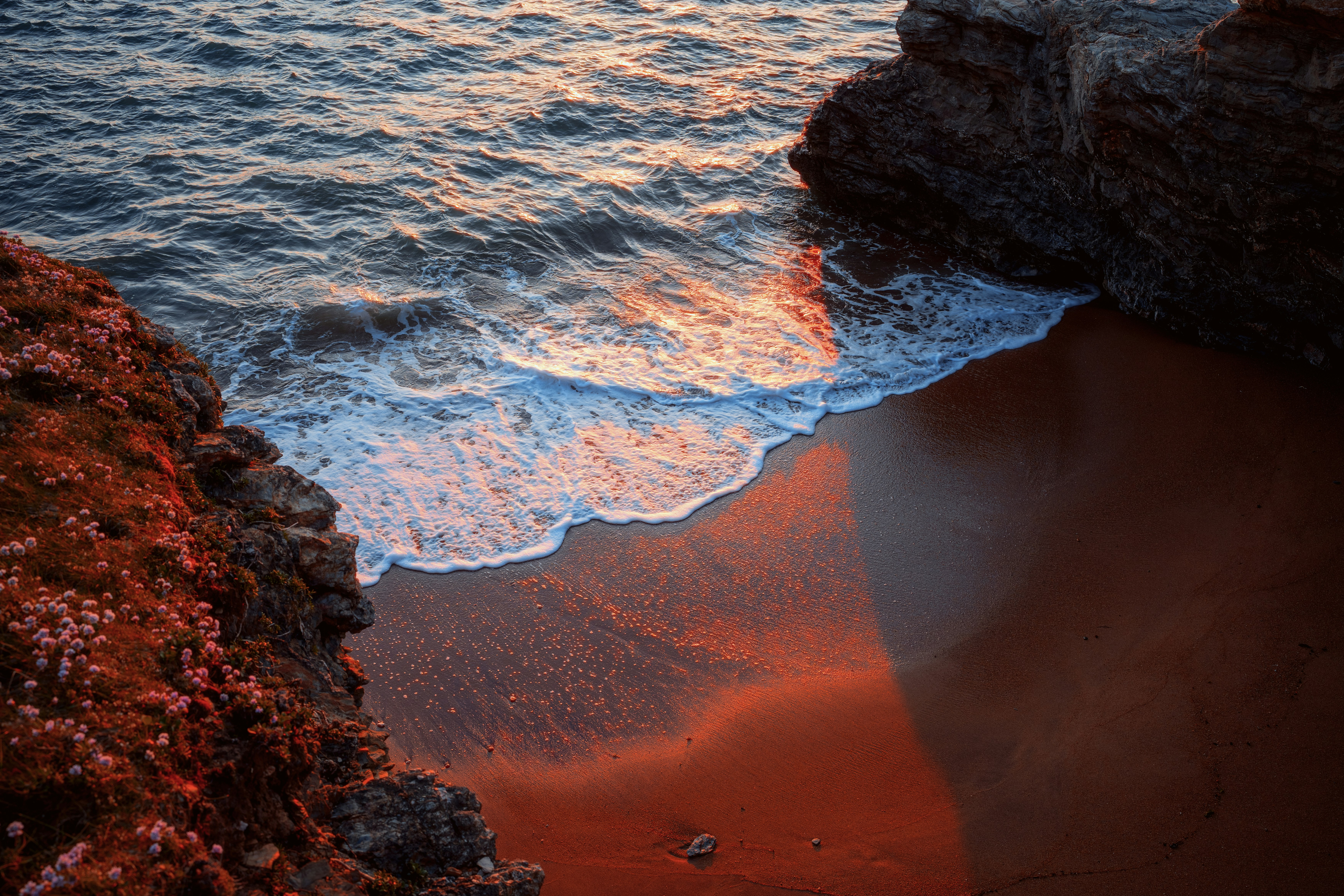 Crescent Tide: Sunset Light on Red Sands Fringed by Dark Cliffs