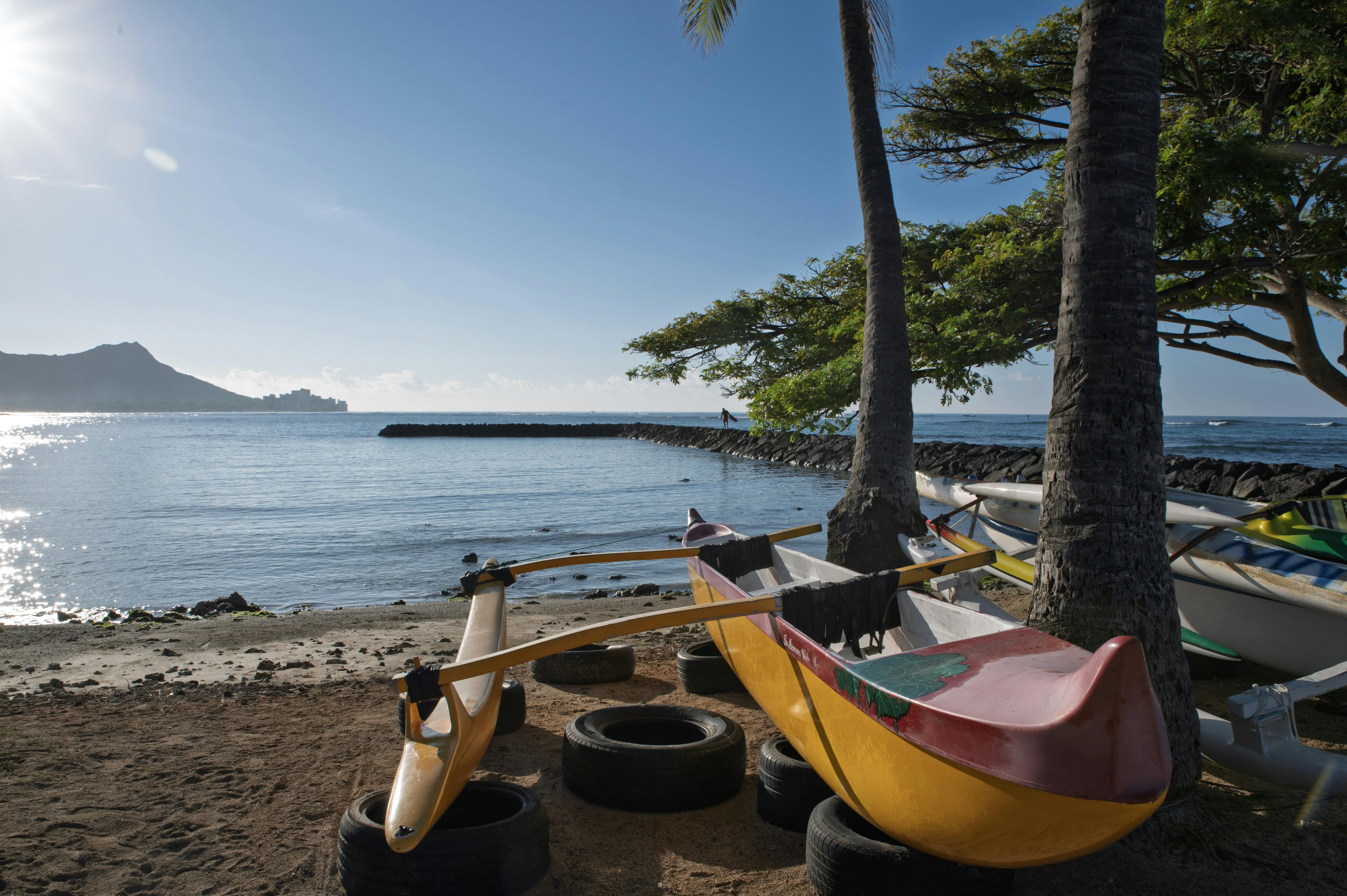Sunlit Boats Rest on Tropical Beach Before Emerald Sea