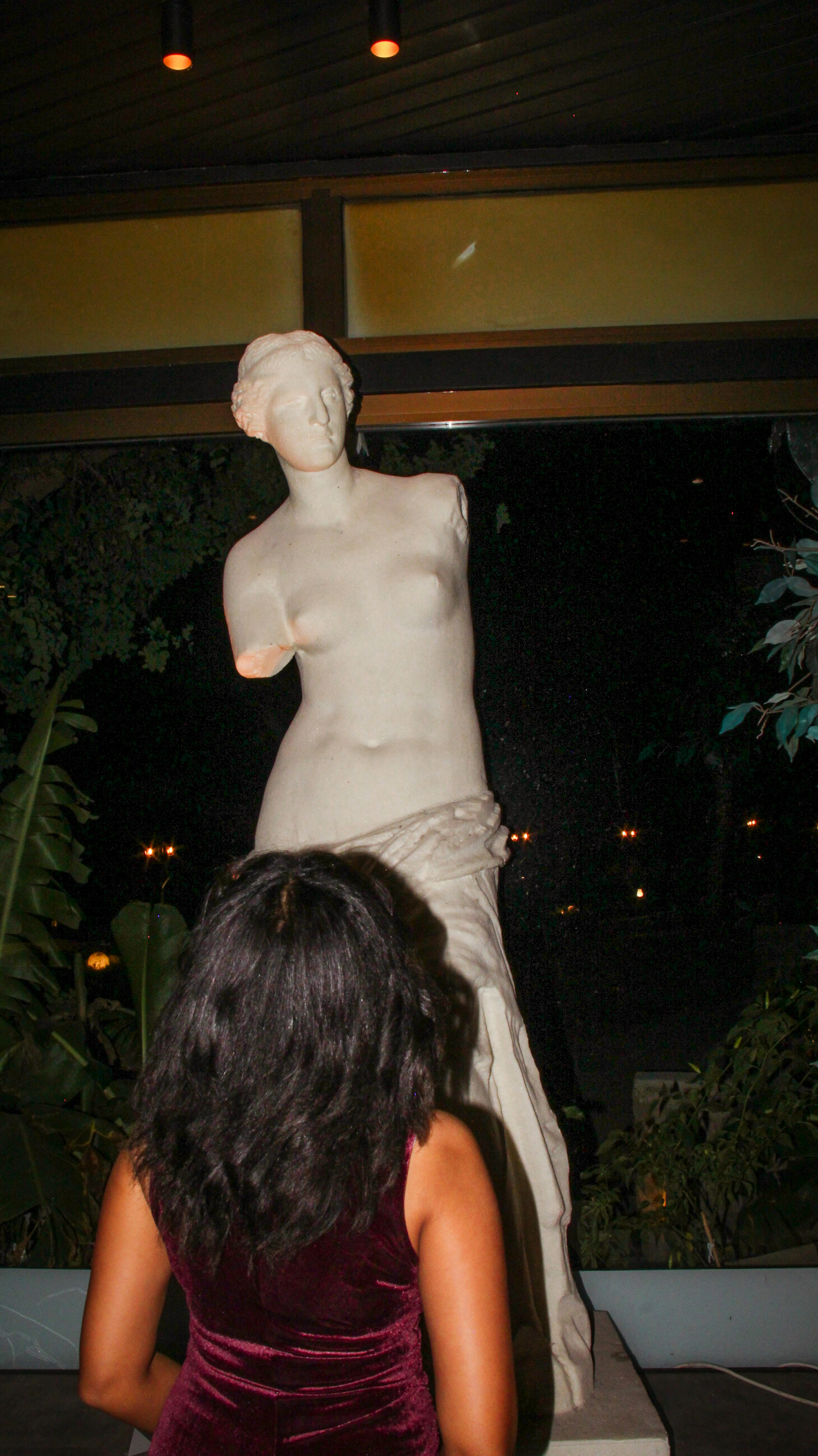 Statue in Spotlight: A Female Figure Stares Down from Night Garden