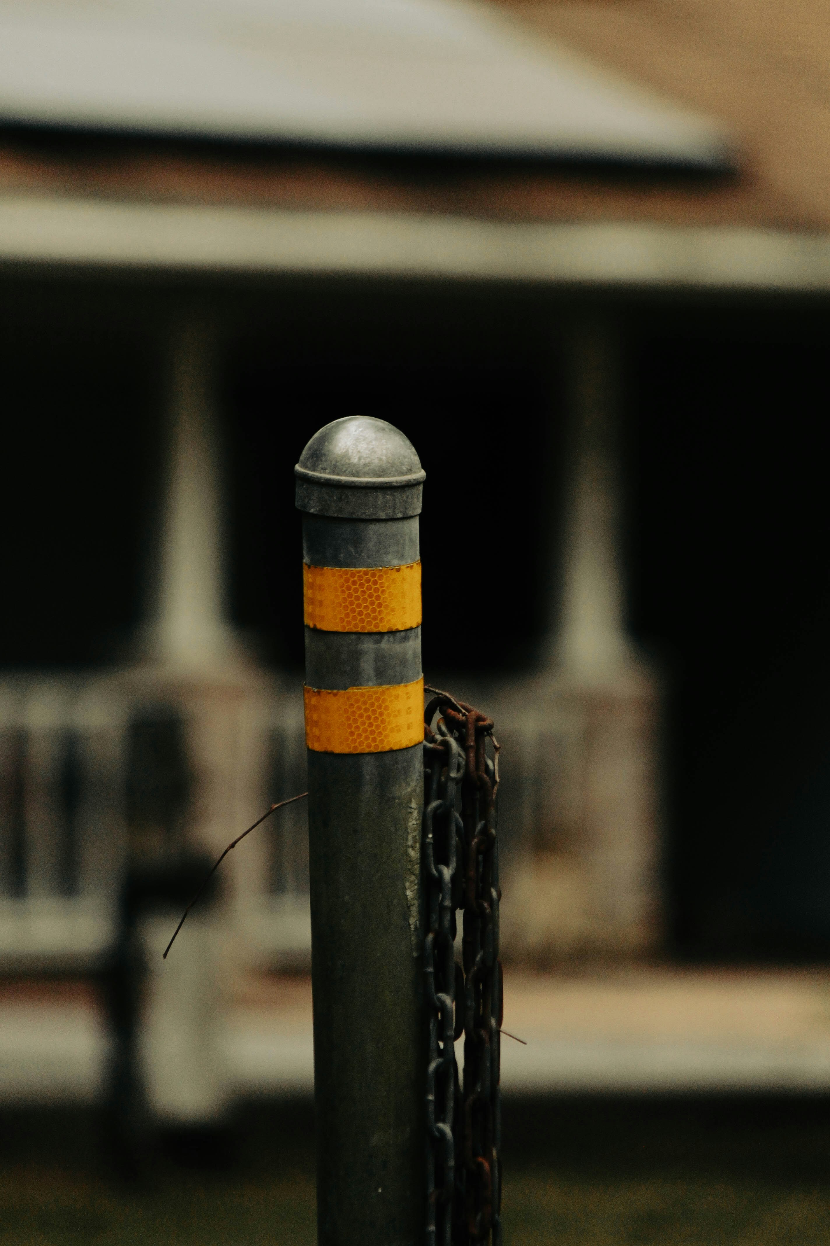 Yellow-Ringed Post in Focus: A Close-Up of a Weathered Barrier