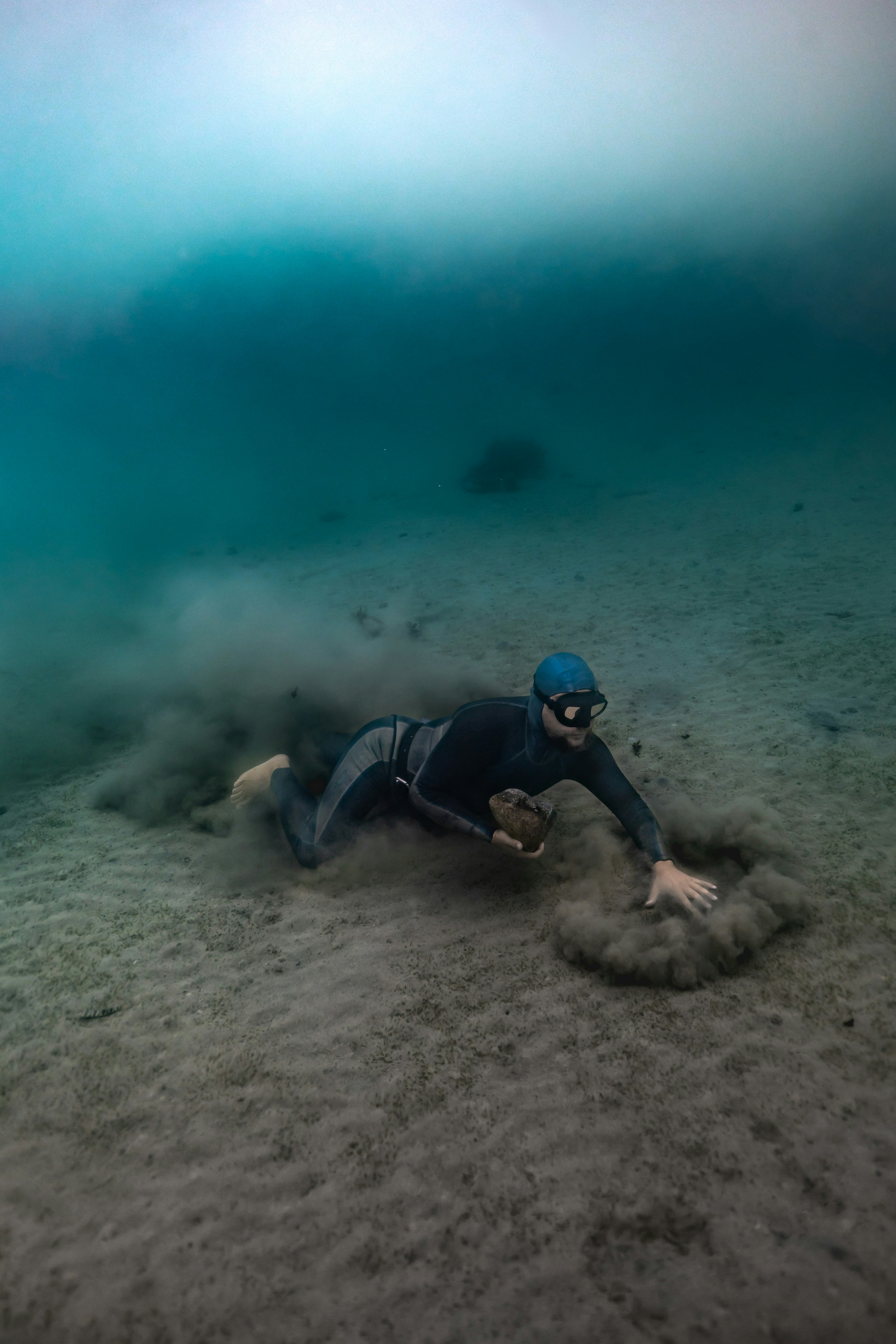 Underwater Diver Reaching for Sand Dust Cloud