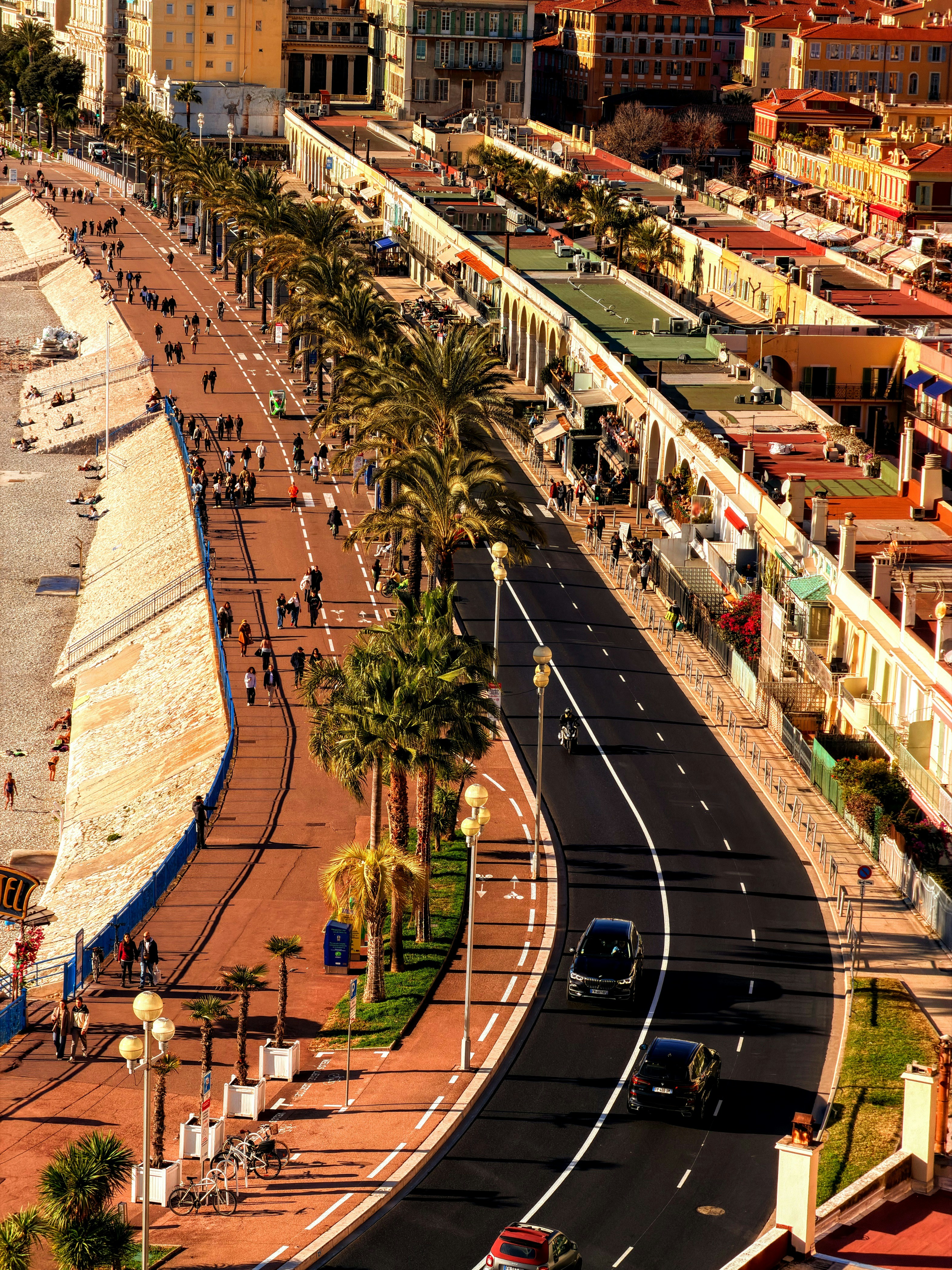 A palm-lined boulevard bending past pastel façades and a sunlit promenade