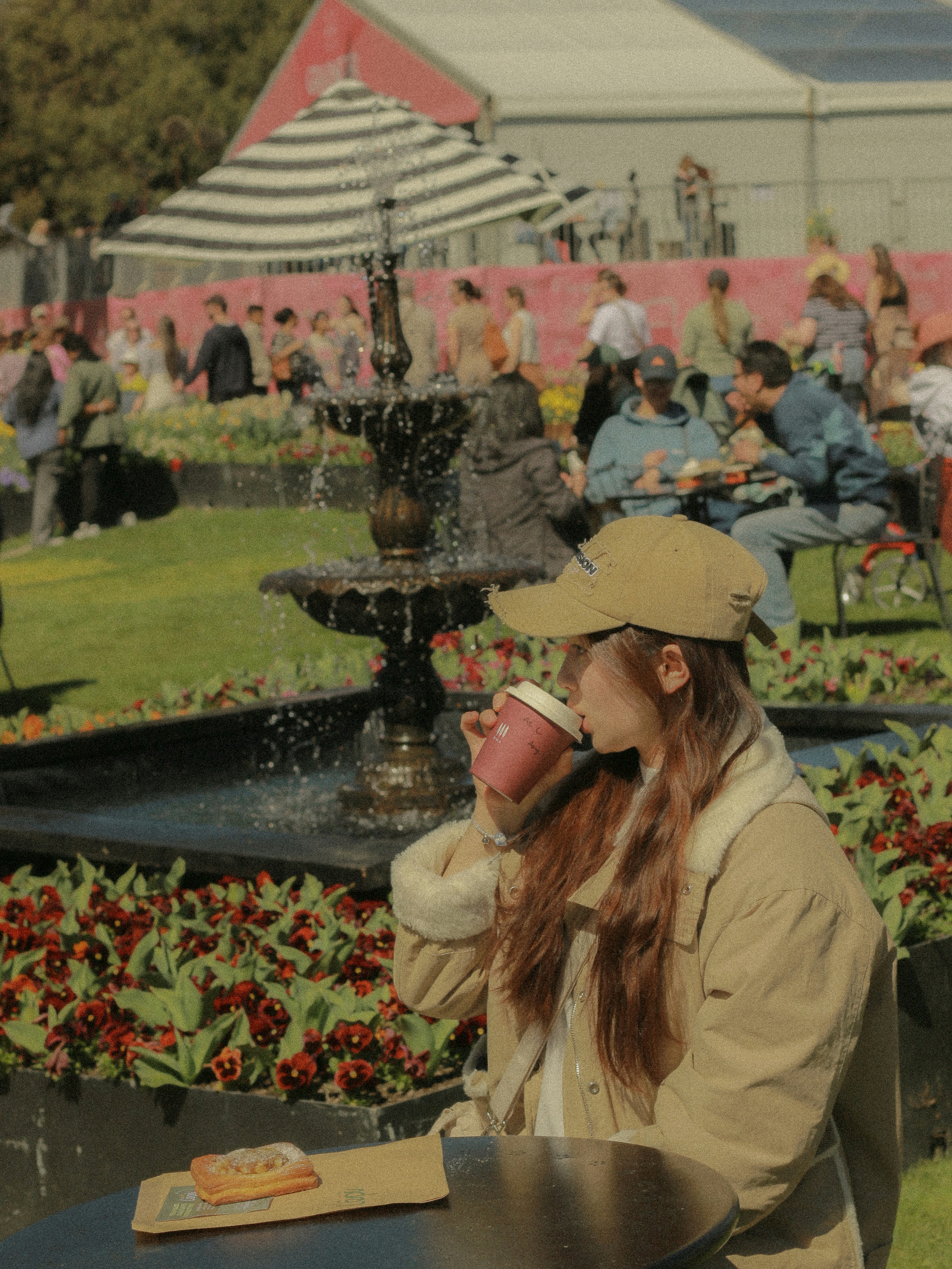Cafe by the fountain: a peach cap and coffee in hand