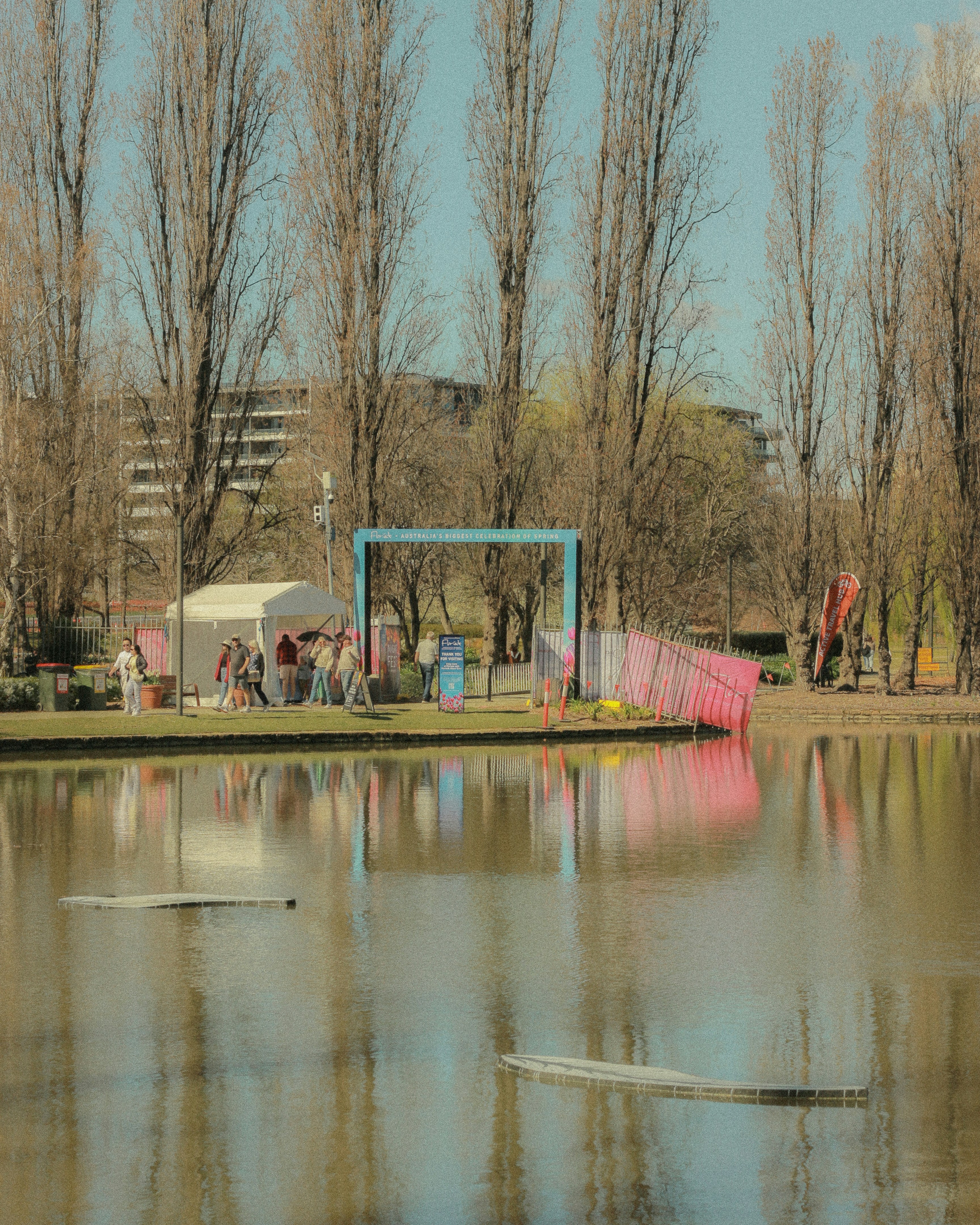 Teal Frame Portal: People Gather at the Water’s Edge by a Timeless Park
