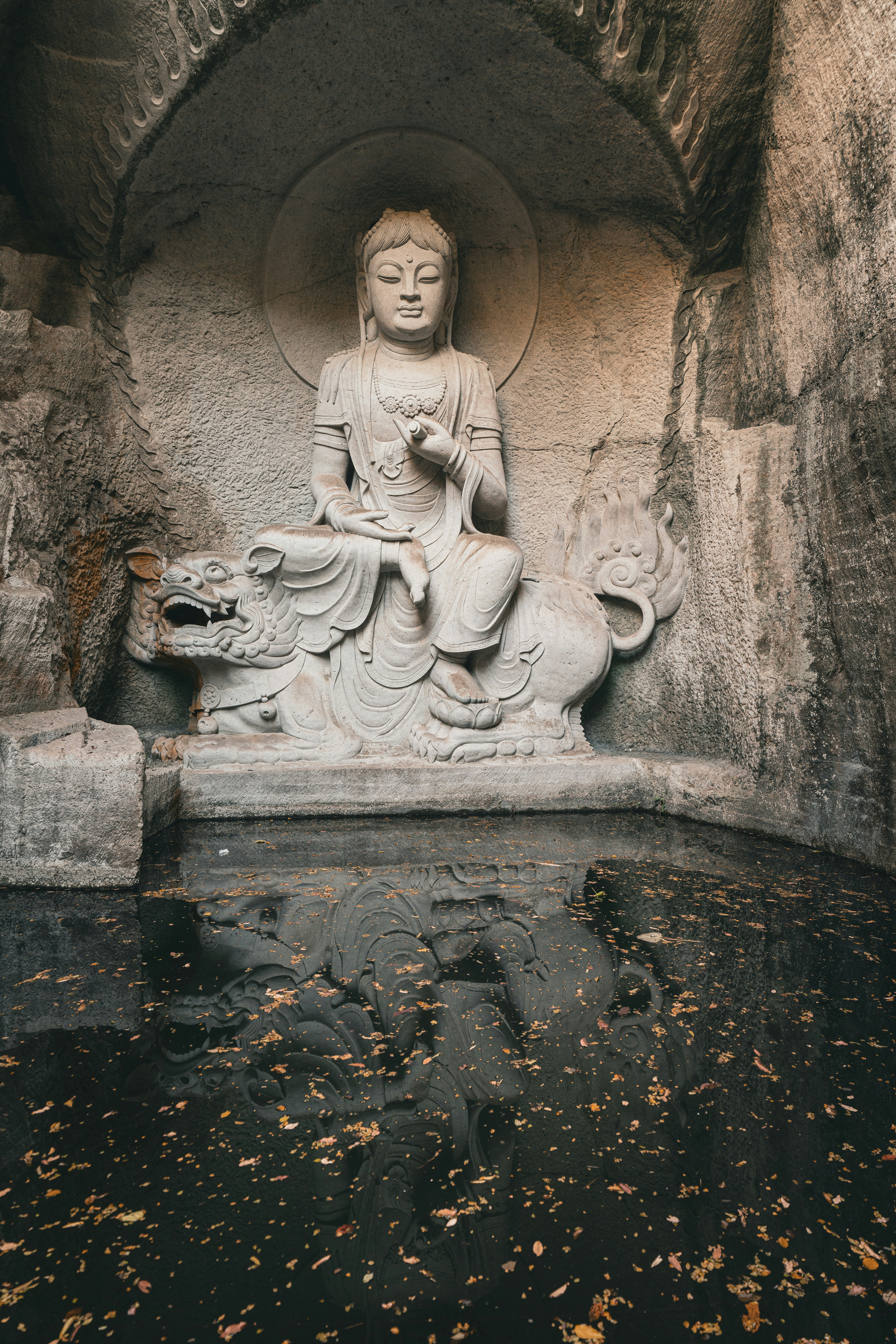 Serene Buddha Amid Reflections: Stone Carved Quiet by the Water