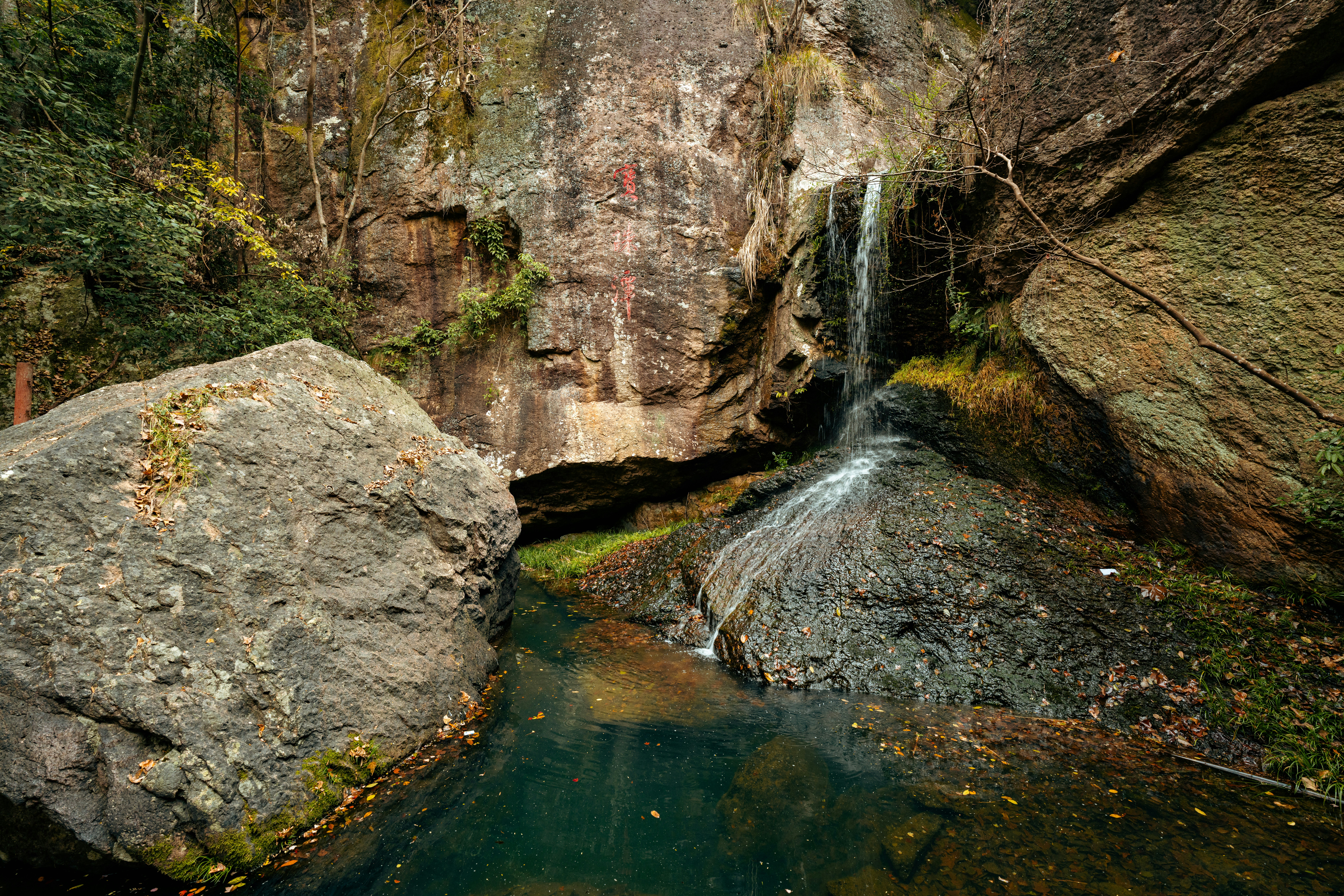 Quiet Cascade Between Weathered Rocks Into a Tinted Pool