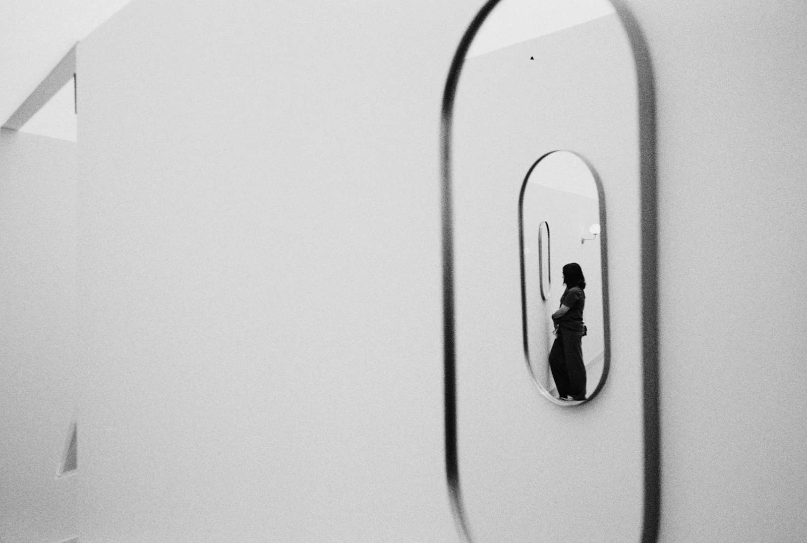 Mirrored Silent Corridor: A Figure in the Lens of an Elliptical Doorway