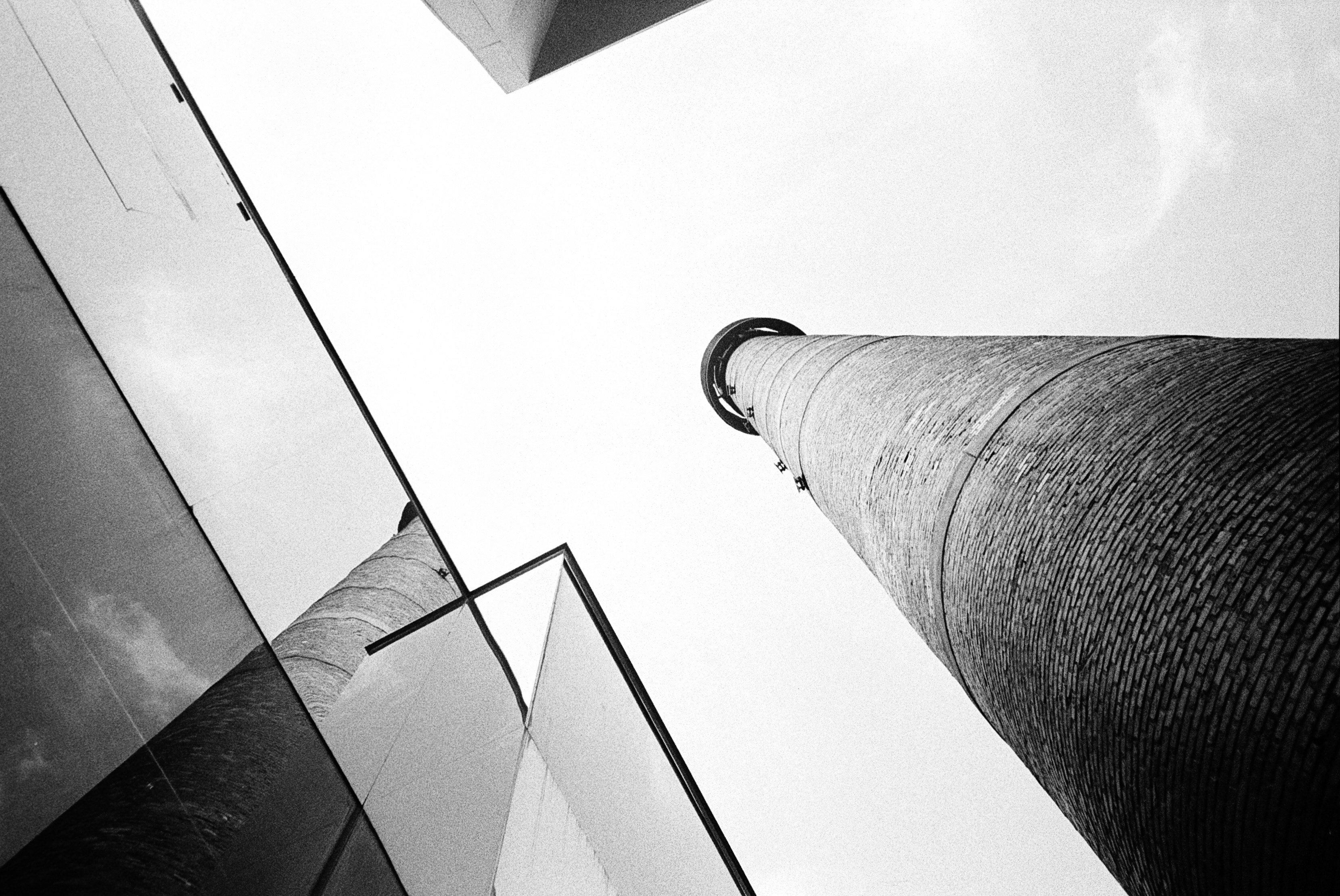 Tall brick chimney against a bright sky.