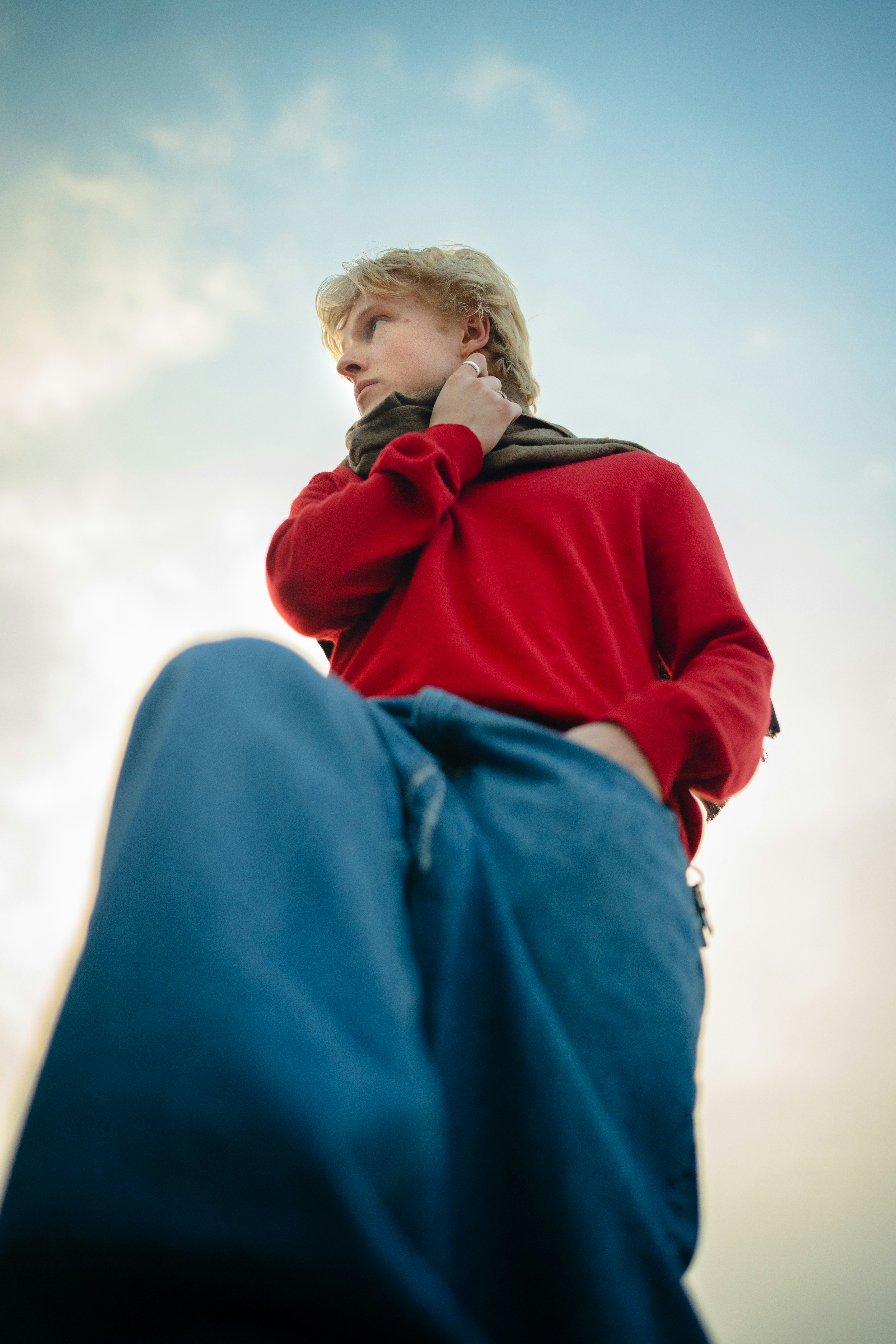 Red Sweater, Blue Jeans, Skybound Gaze: A Low-Angle Portrait