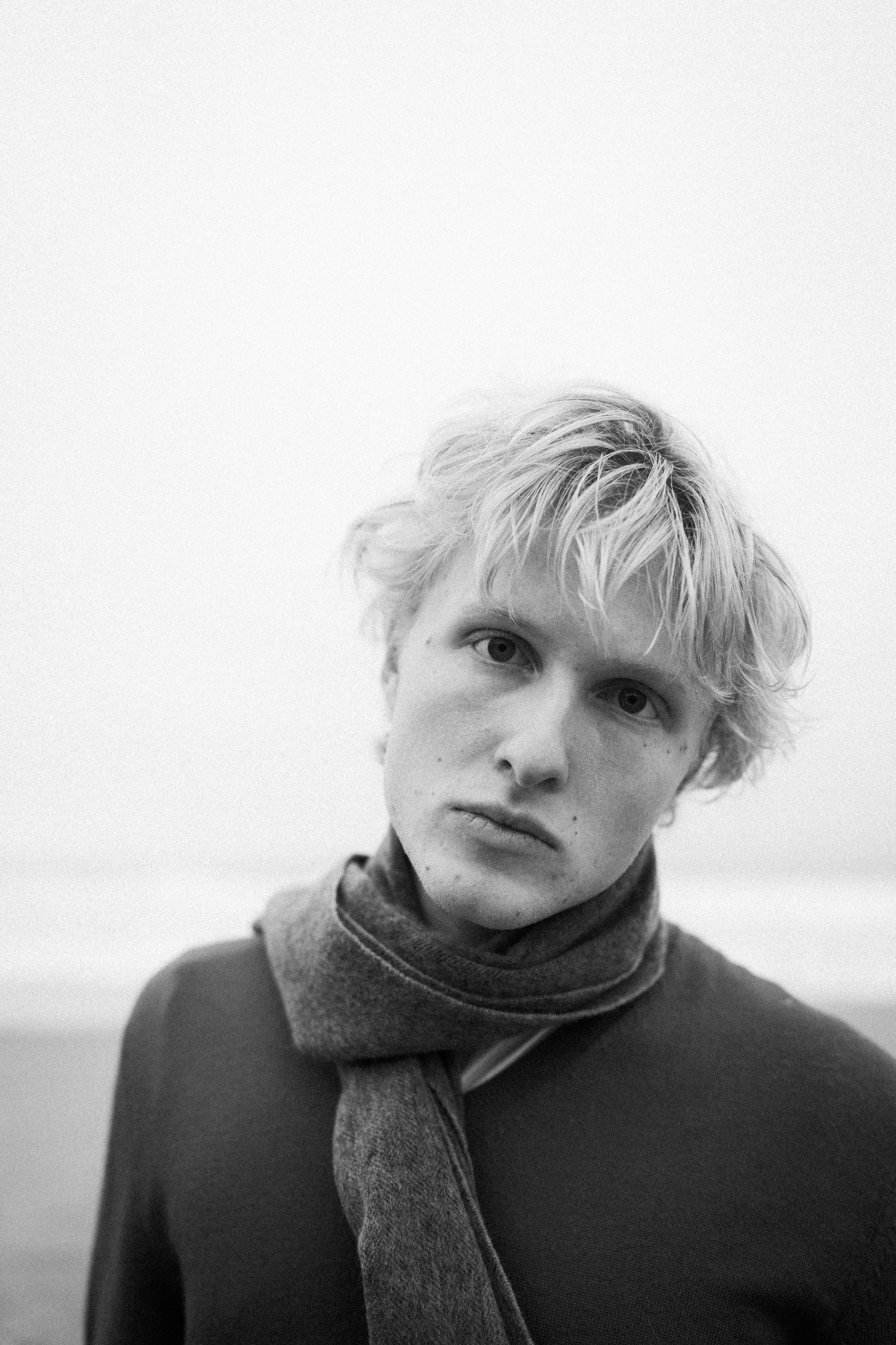 Tilted gaze, soft winterscape: a minimalist portrait in grayscale