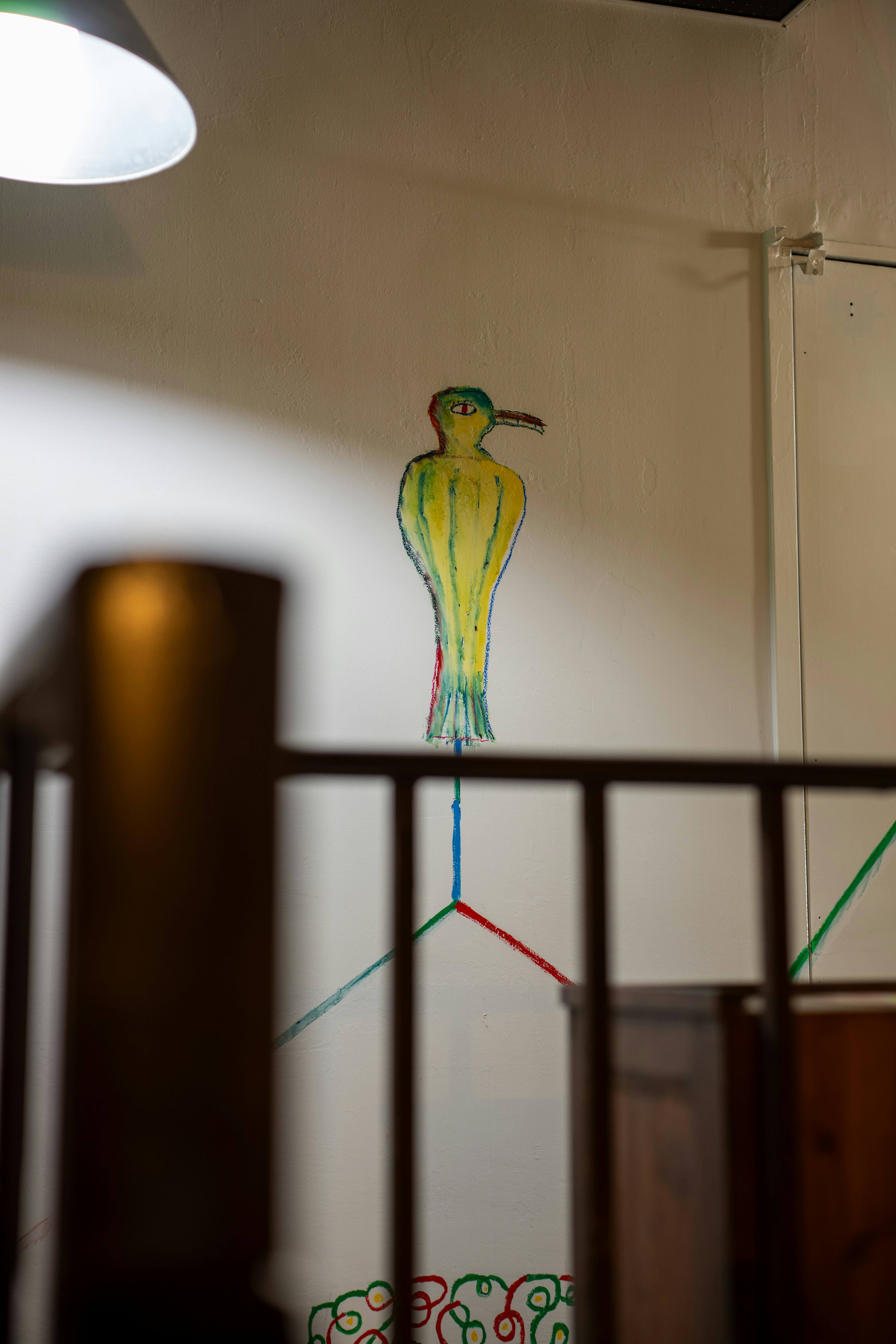 Colorful mural of a perched bird centered under a lofted light