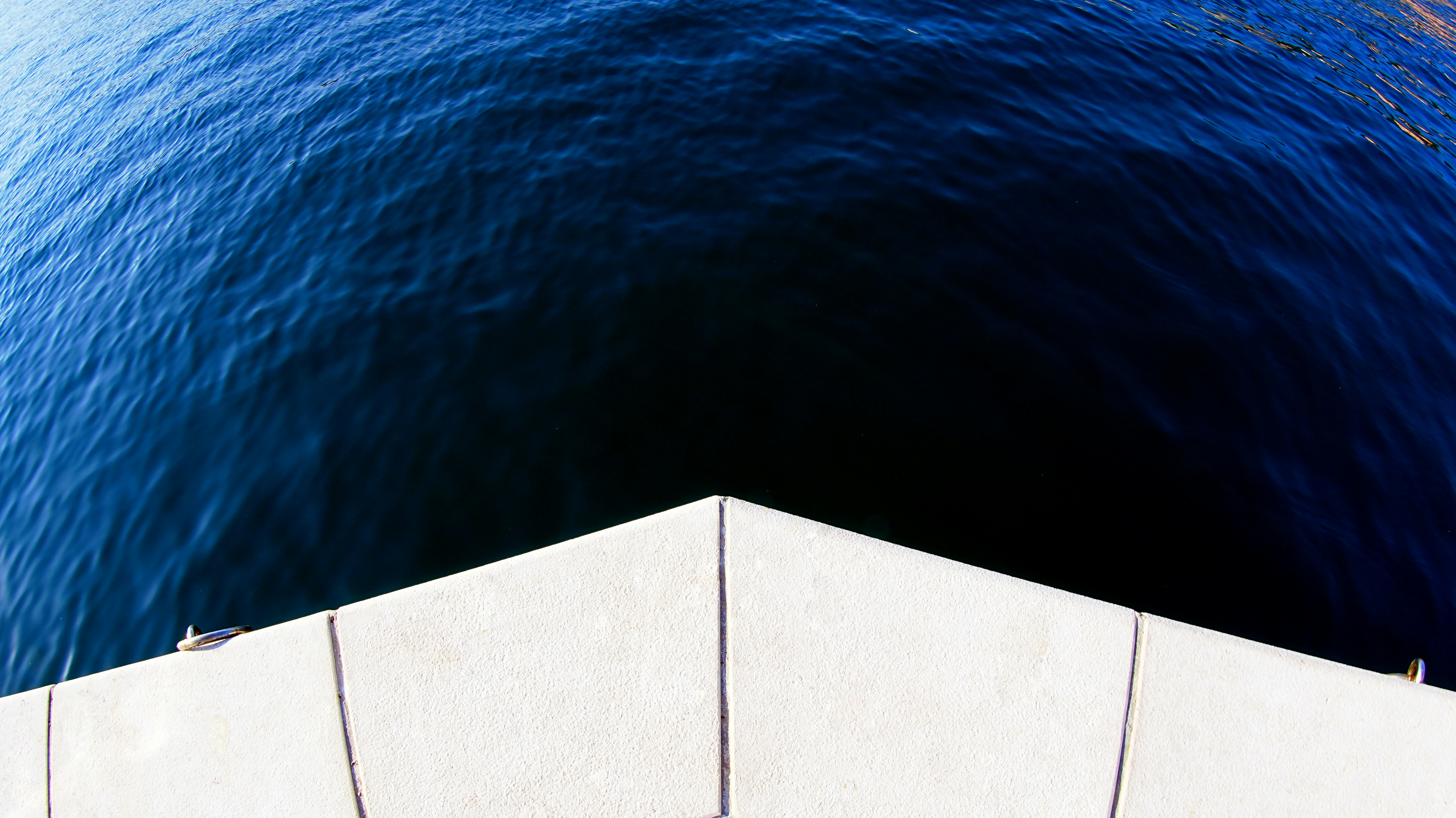 Deep blue ocean water meets a light concrete pier. photo – Free ...
