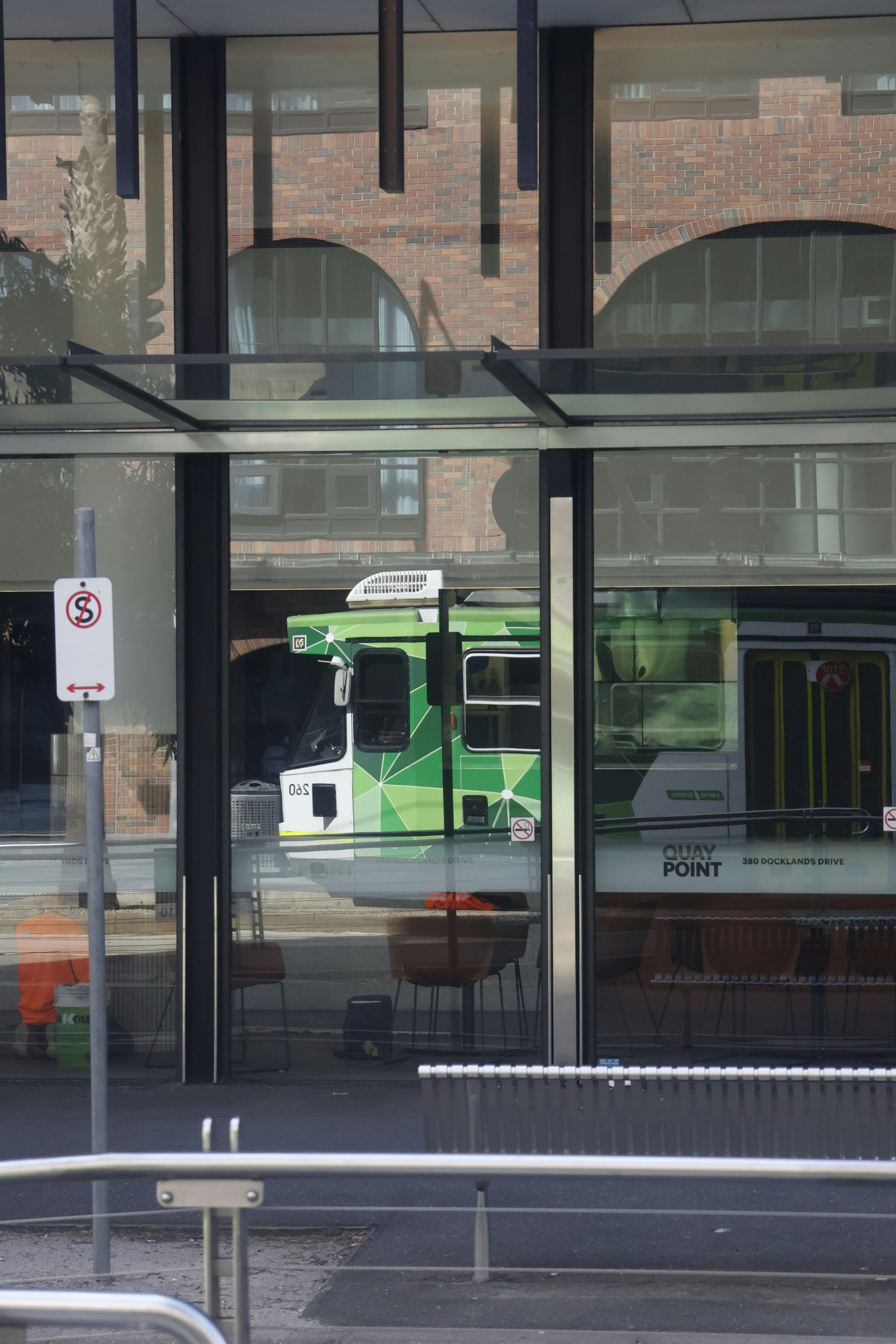 Glass and Rails: Reflections of a Green Tram at the Station