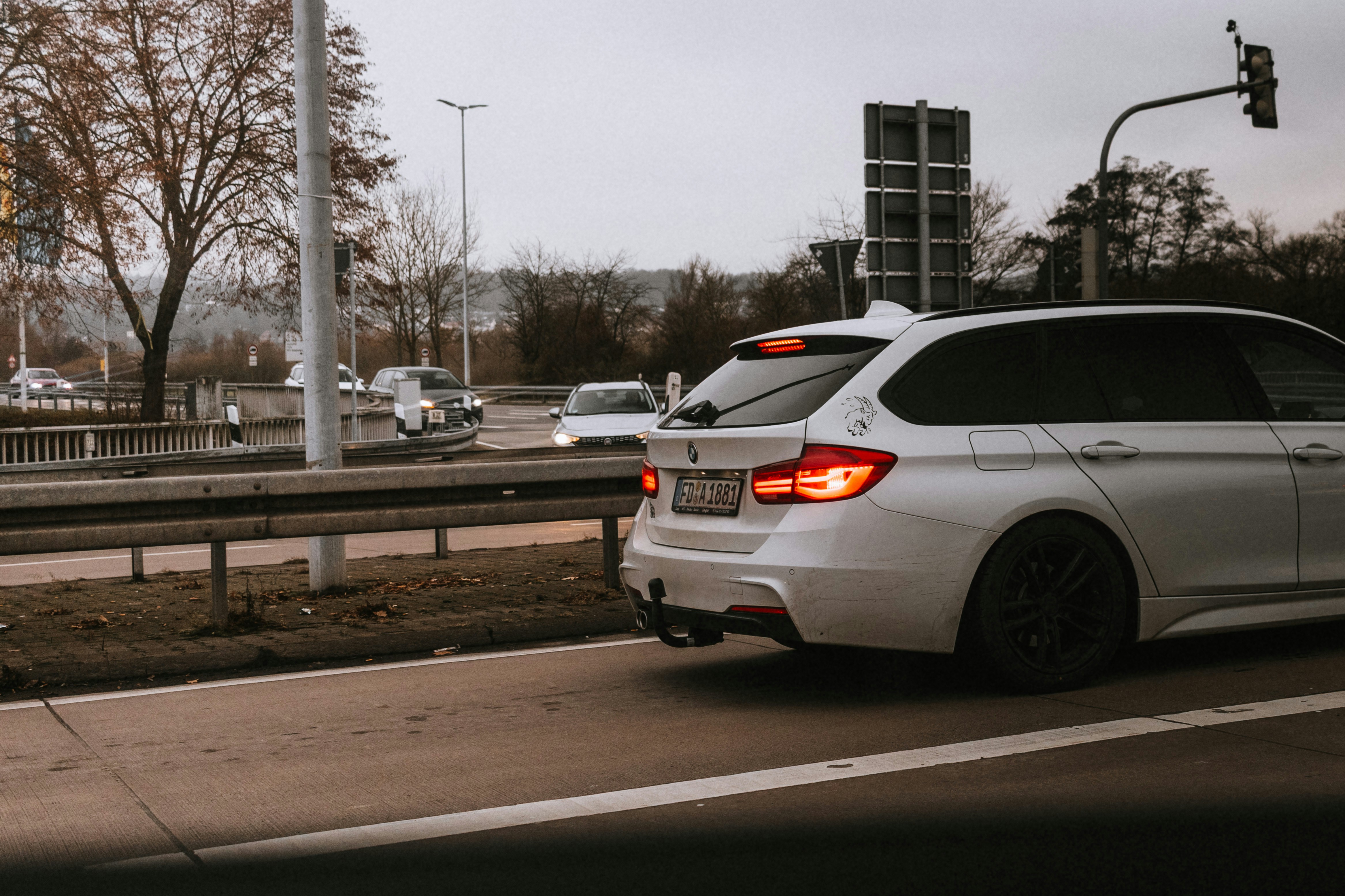 White station wagon driving on a road.