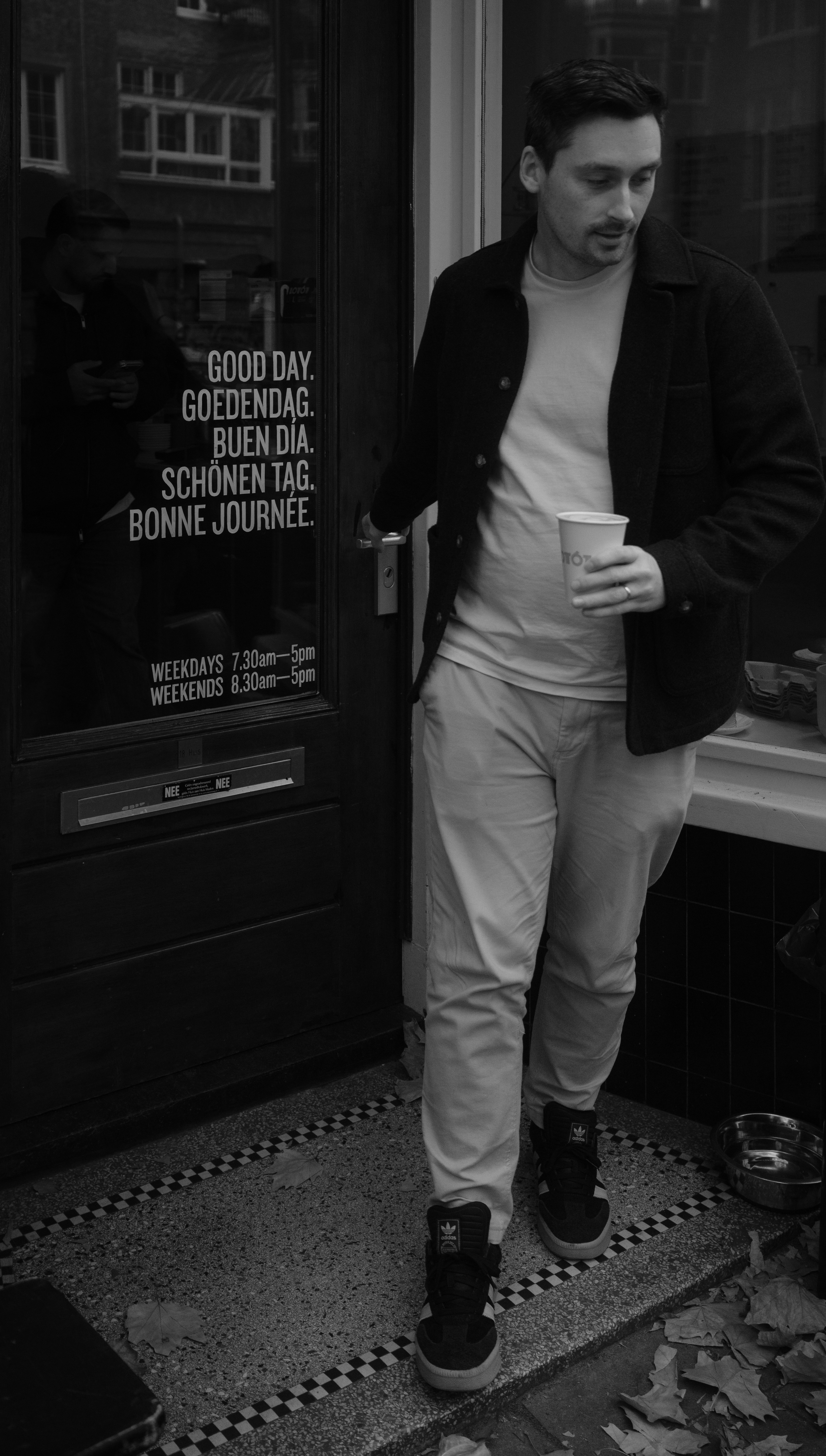 Man holding coffee cup walks out of building photo – Free Street Image ...