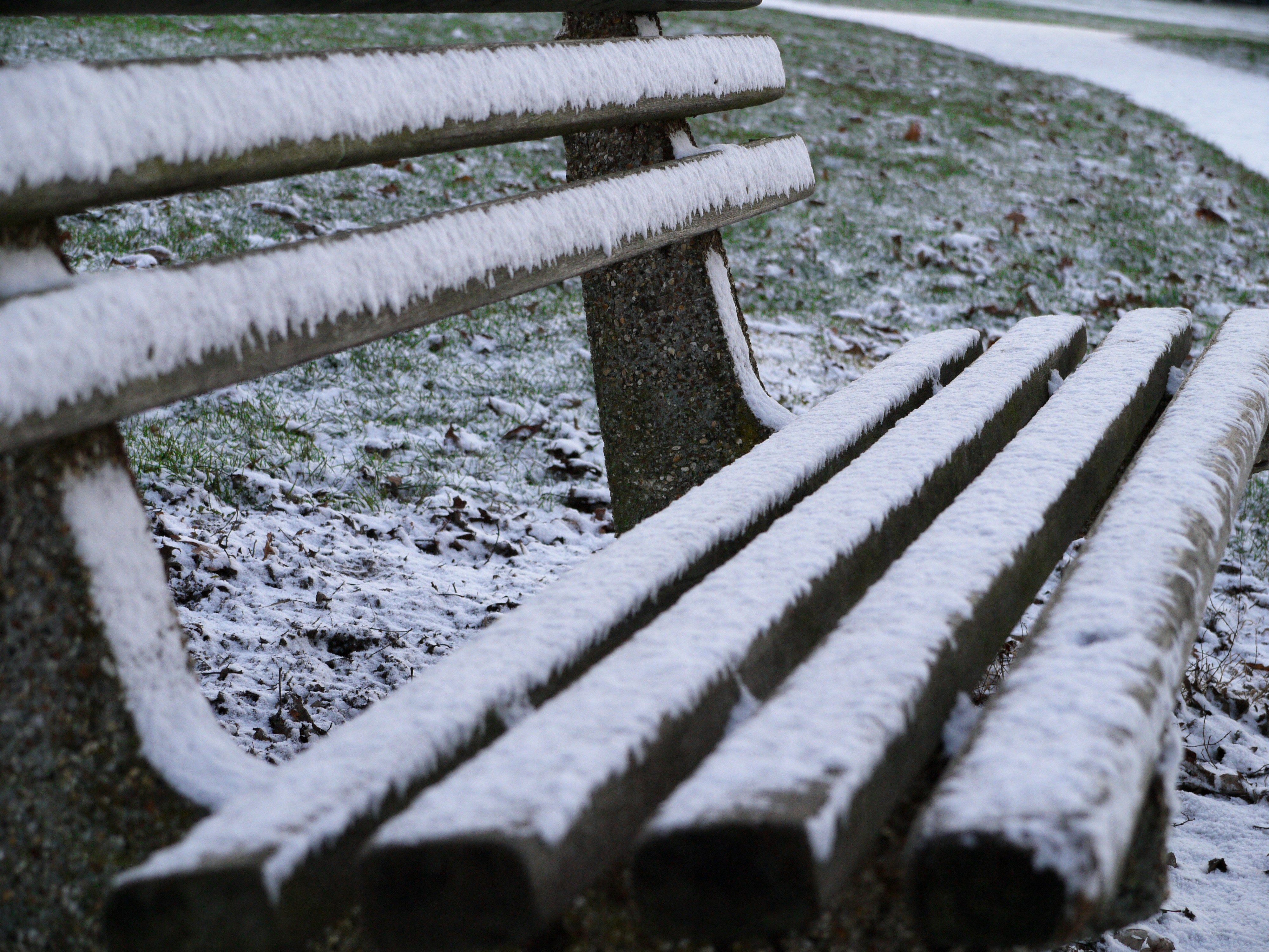 A wooden park bench covered in snow