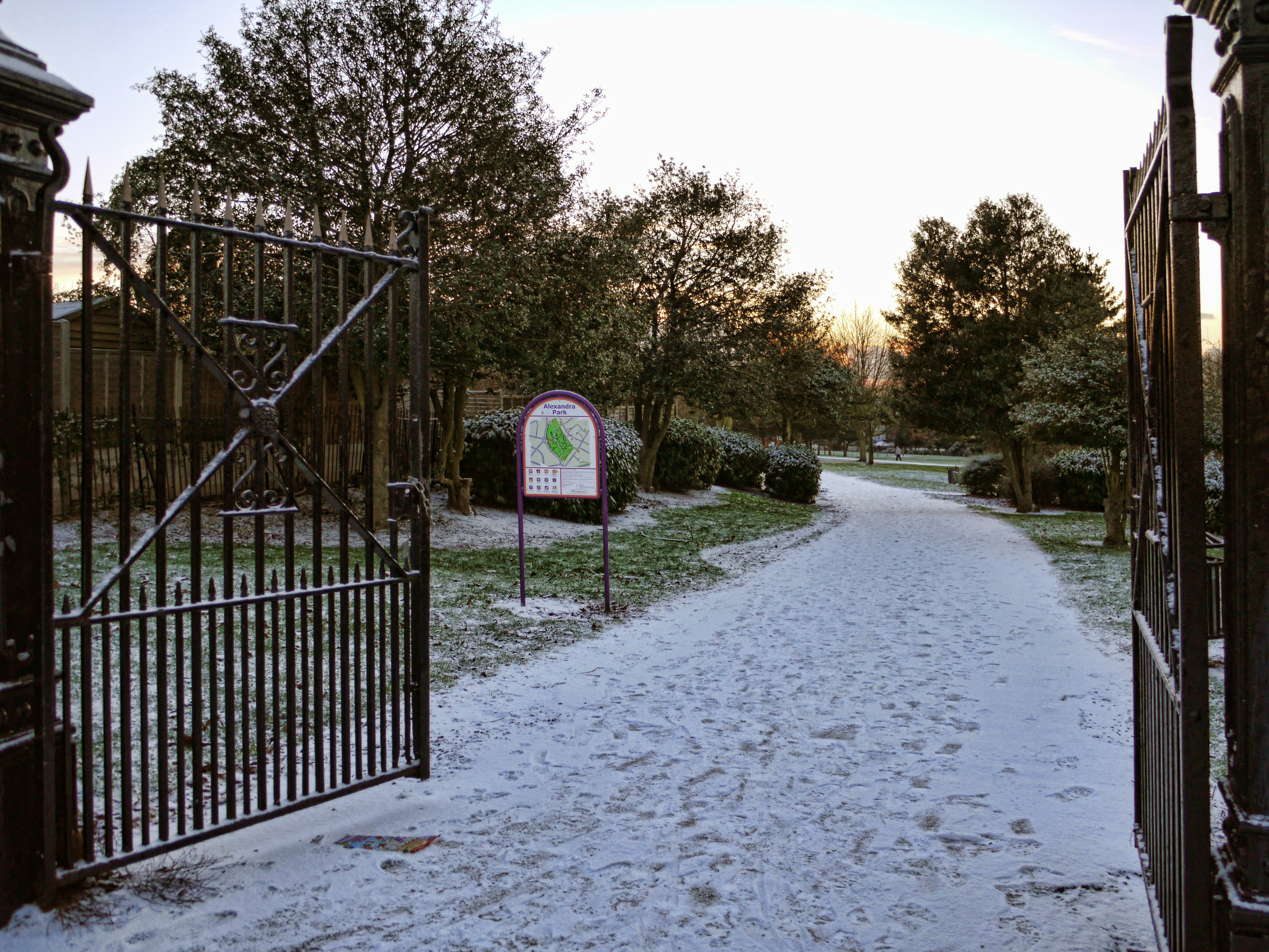 Open gates lead to a snowy park path.