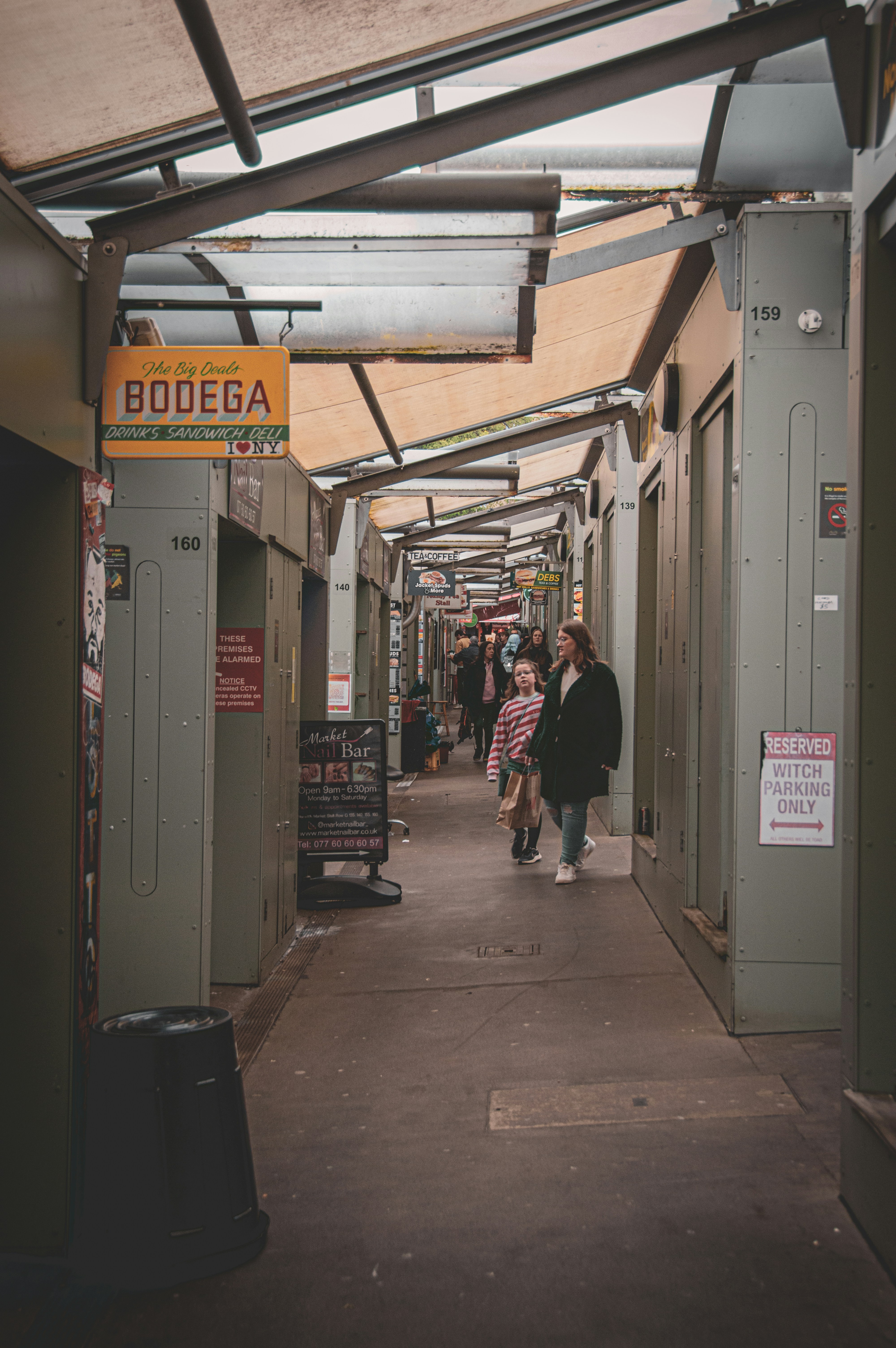 Laneway of Echoes: People Walk the Corridor of Small Shops
