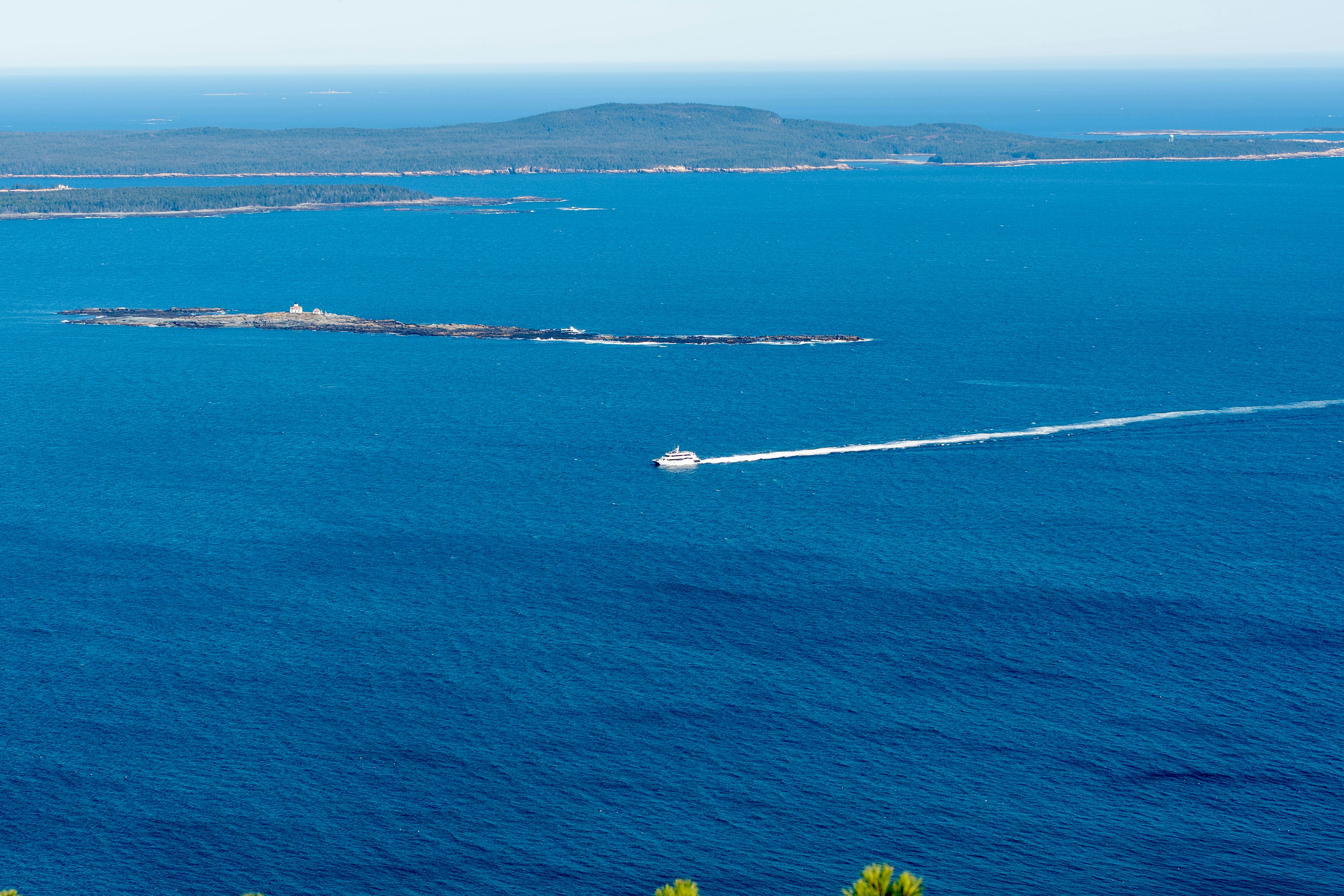White Vessel Tracing a Quiet Wake Across a Blue Expanse