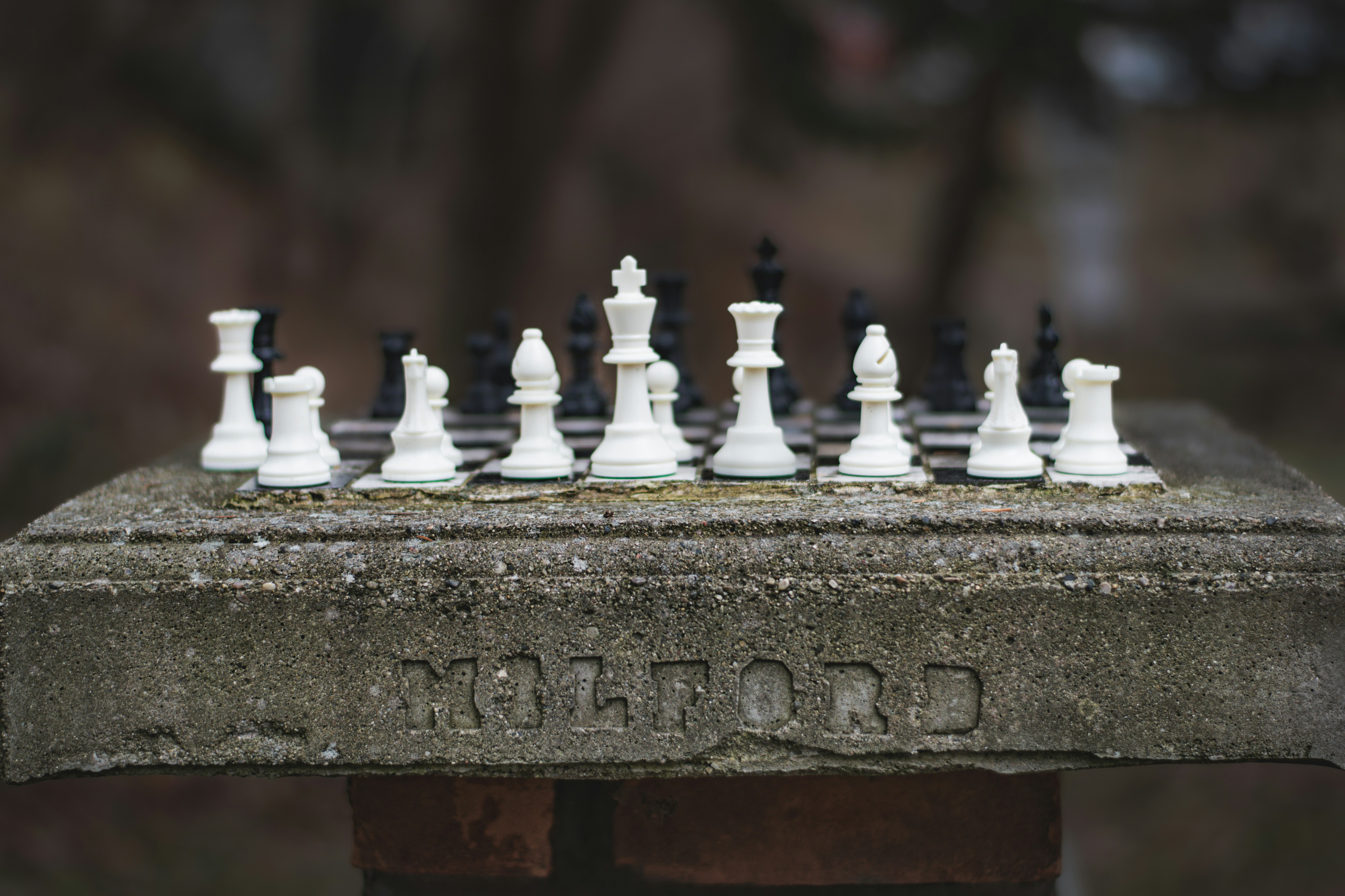 White Chess Figures Stand Vigil on Weathered Plinth