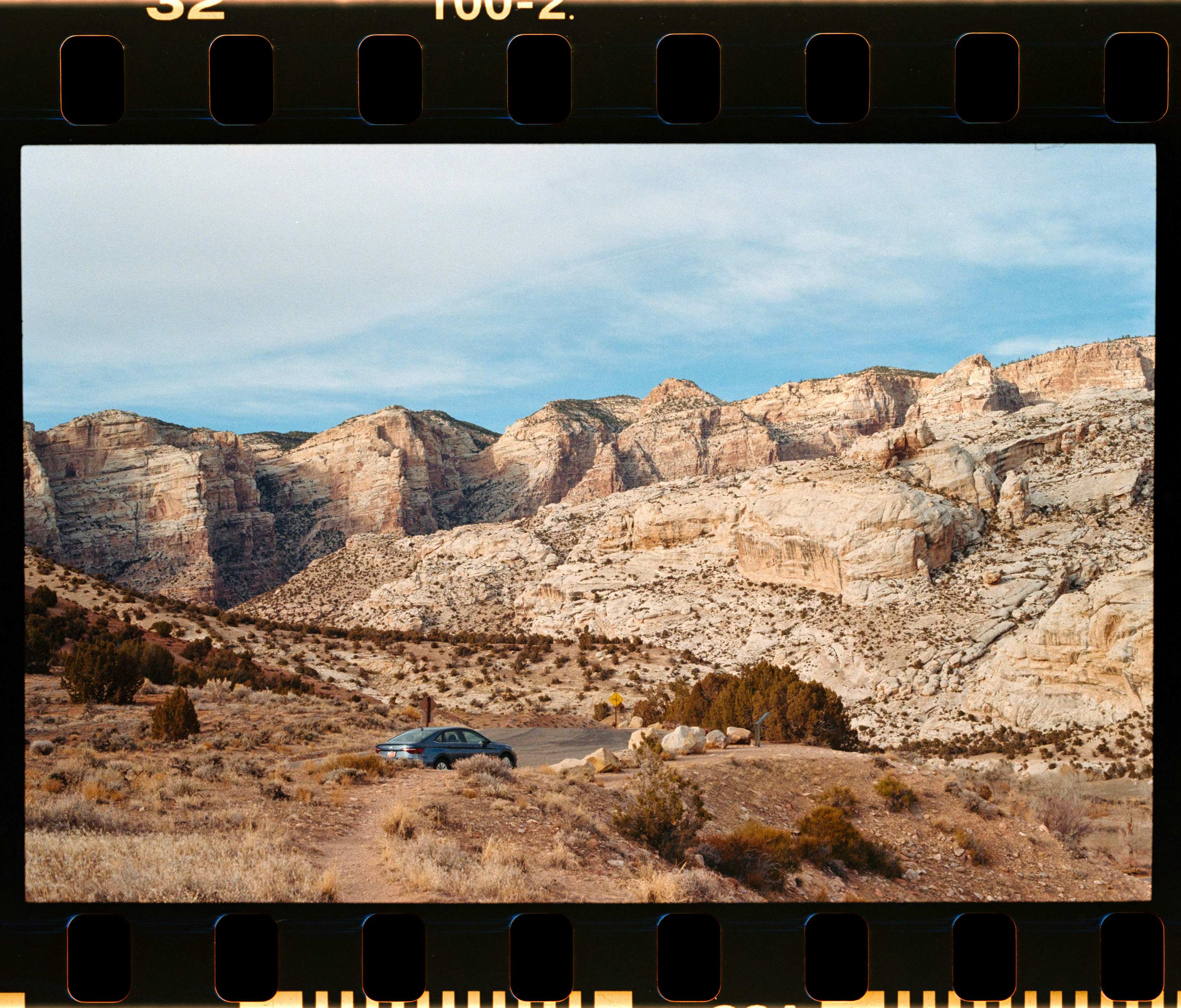 Desert Ridge Drive: A Lonely Car Beneath Layered Canyon Skies