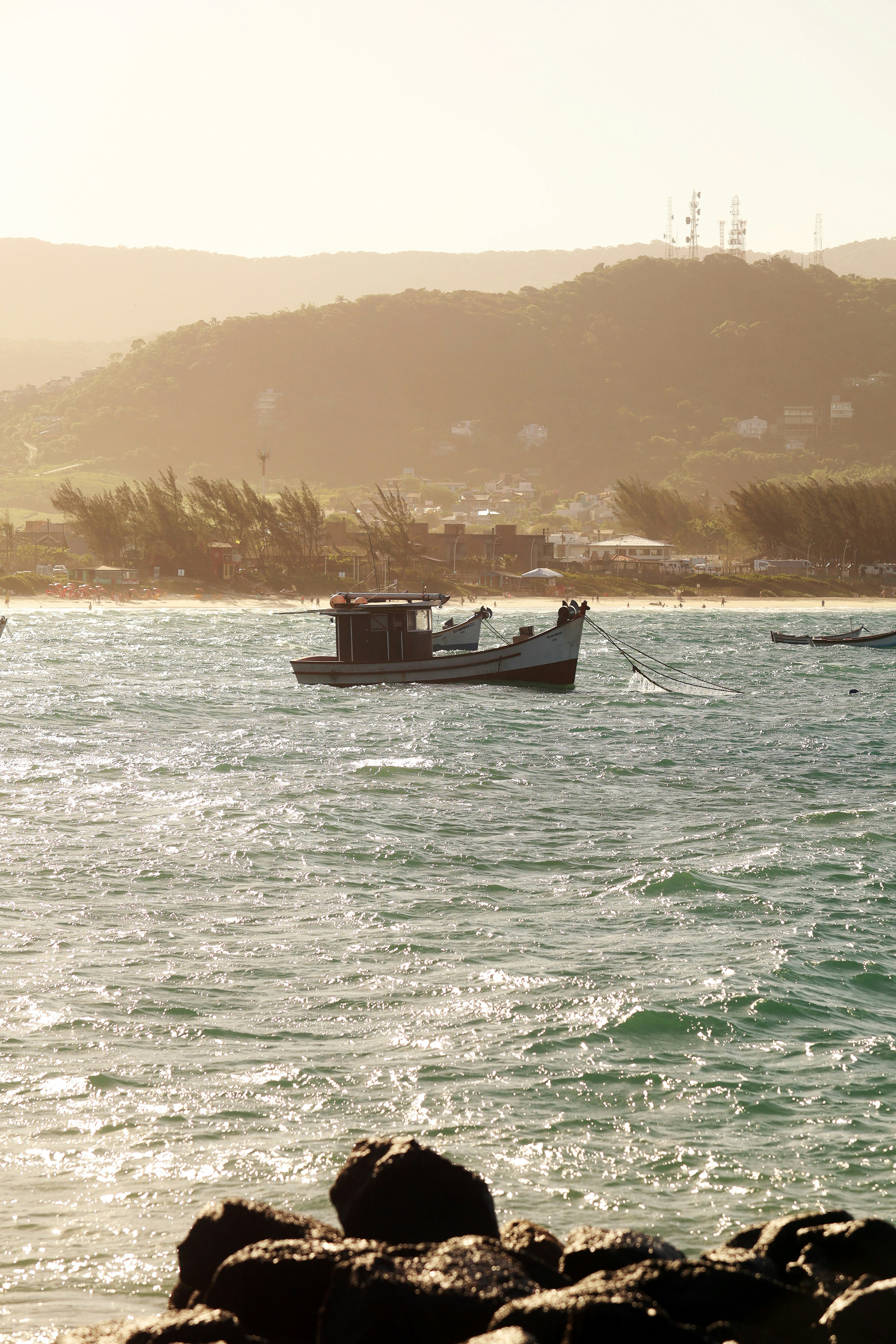 Sunlit Harborside: A Quiet Boat Drifts Amid Warm Coastal Light