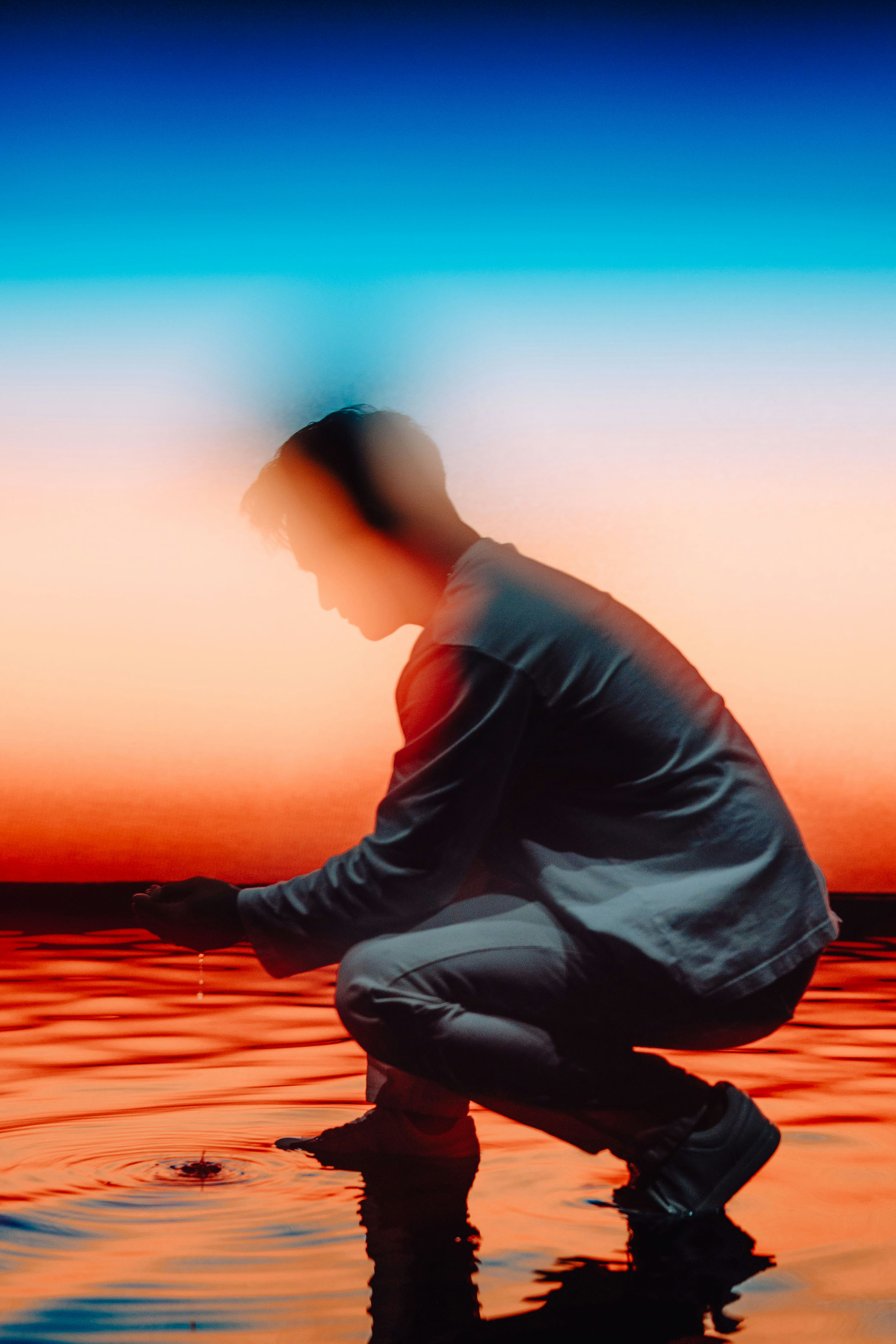Silhouette in the Moment: A Figure Kneels by Sunset-Glazed Water