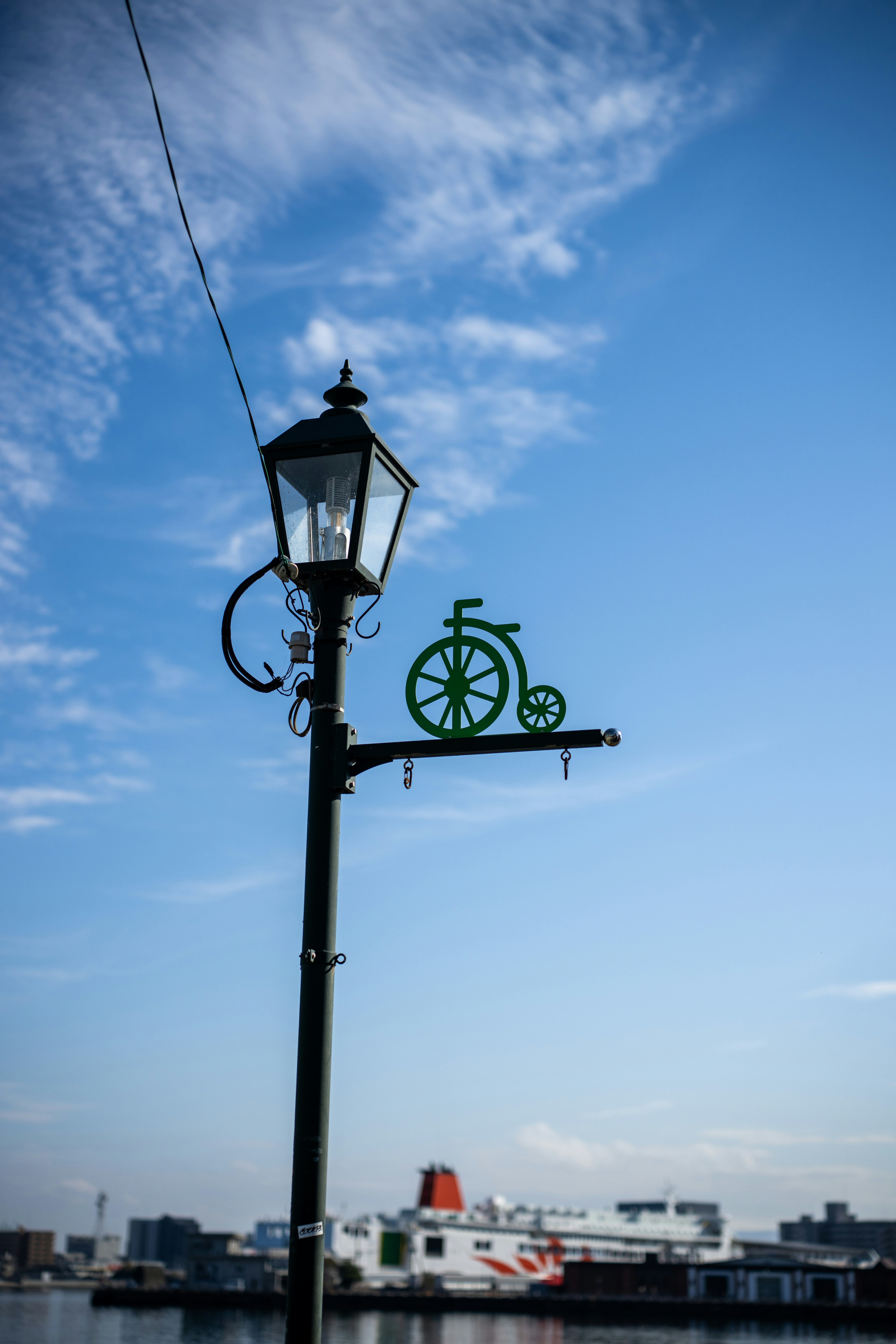 Skyward Signpost: A Green Bicycle Finial Against Open Blue