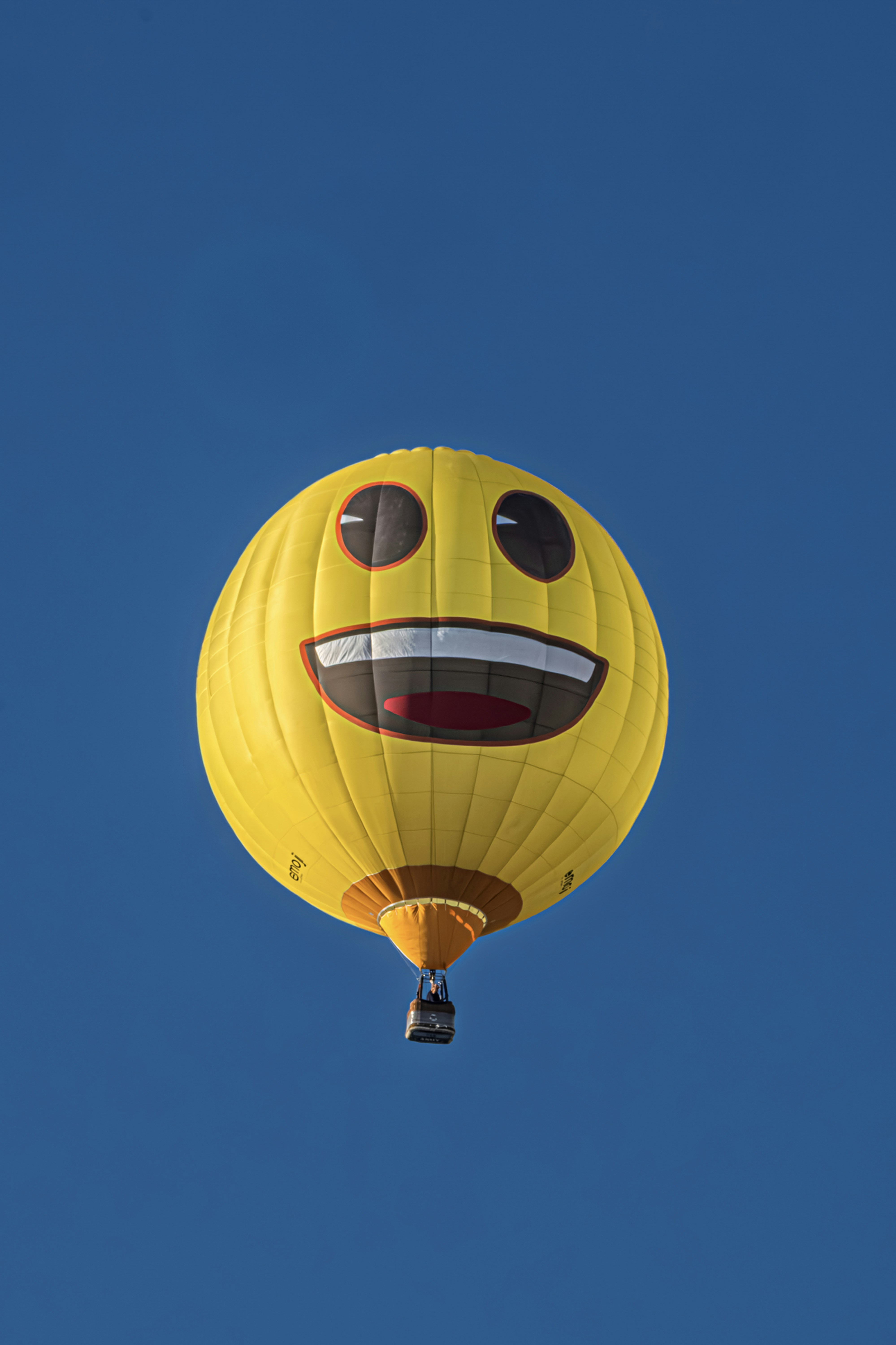 Happy Balloon: A Yellow Emoji Ascends Against a Clear Blue Sky